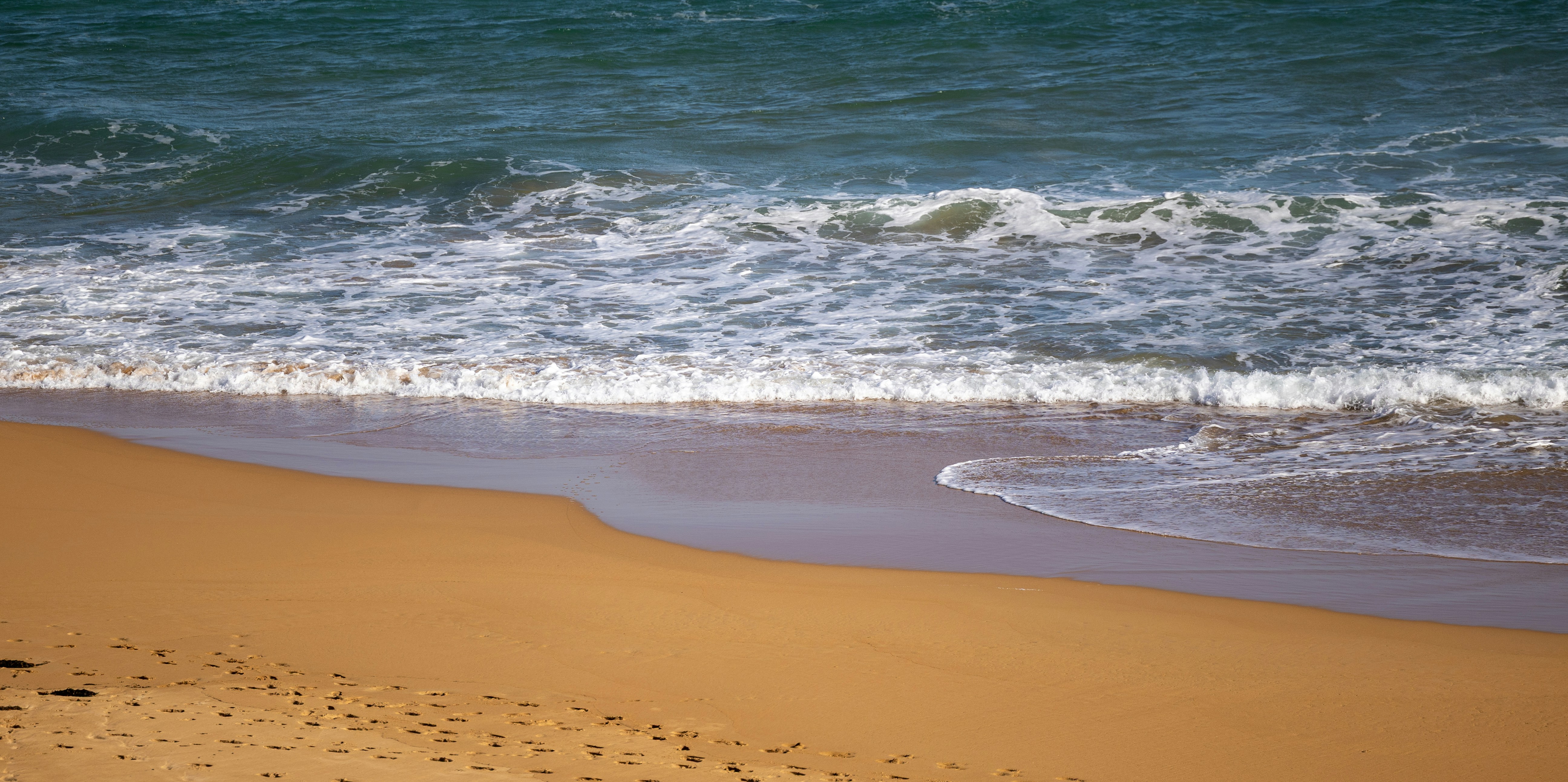 Coastal Calm: Sunlit Sand Meeting a Fading Tide