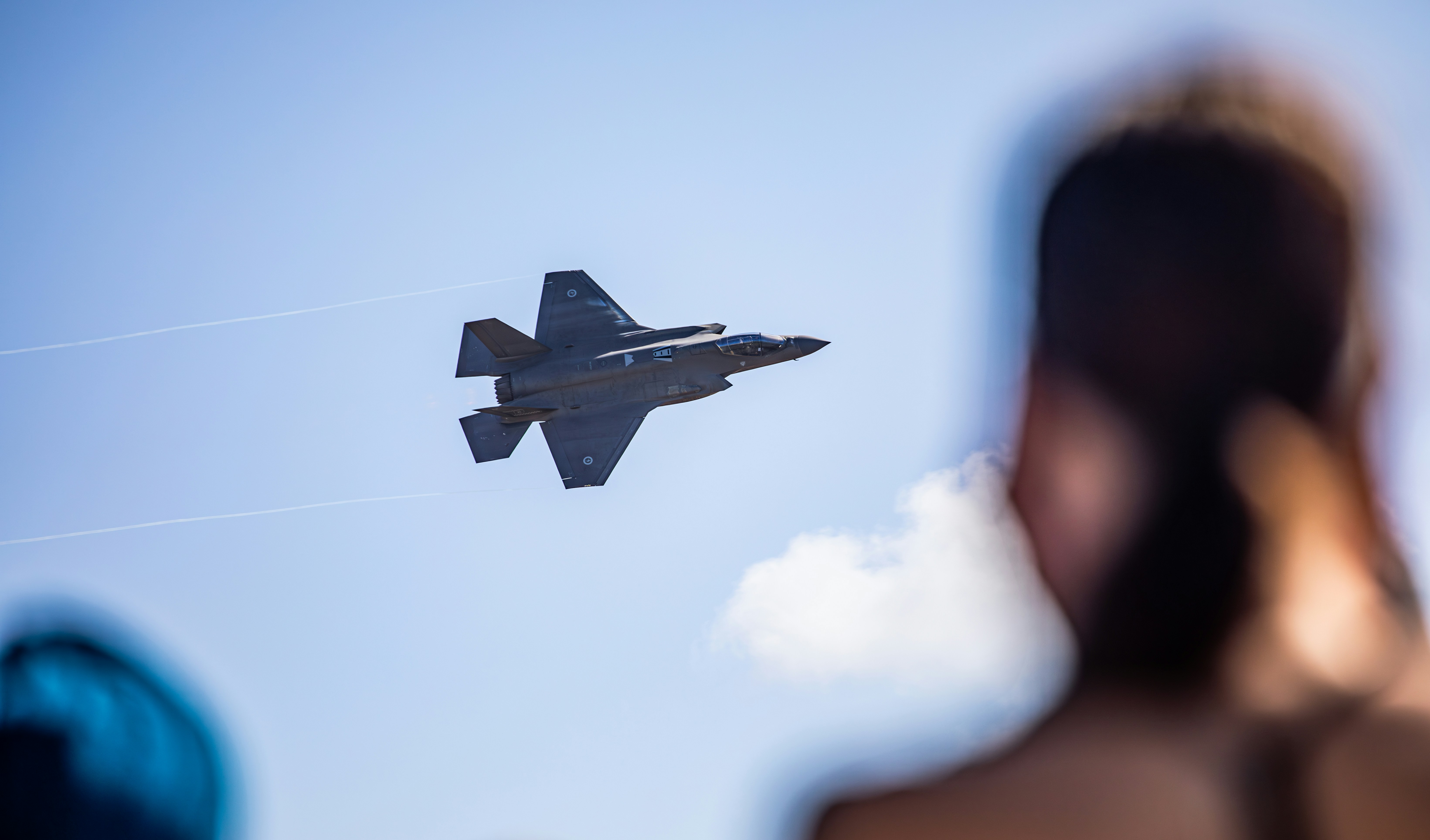 Jet Draws a Streak in the Sky: A blurred crowdBelow Moments