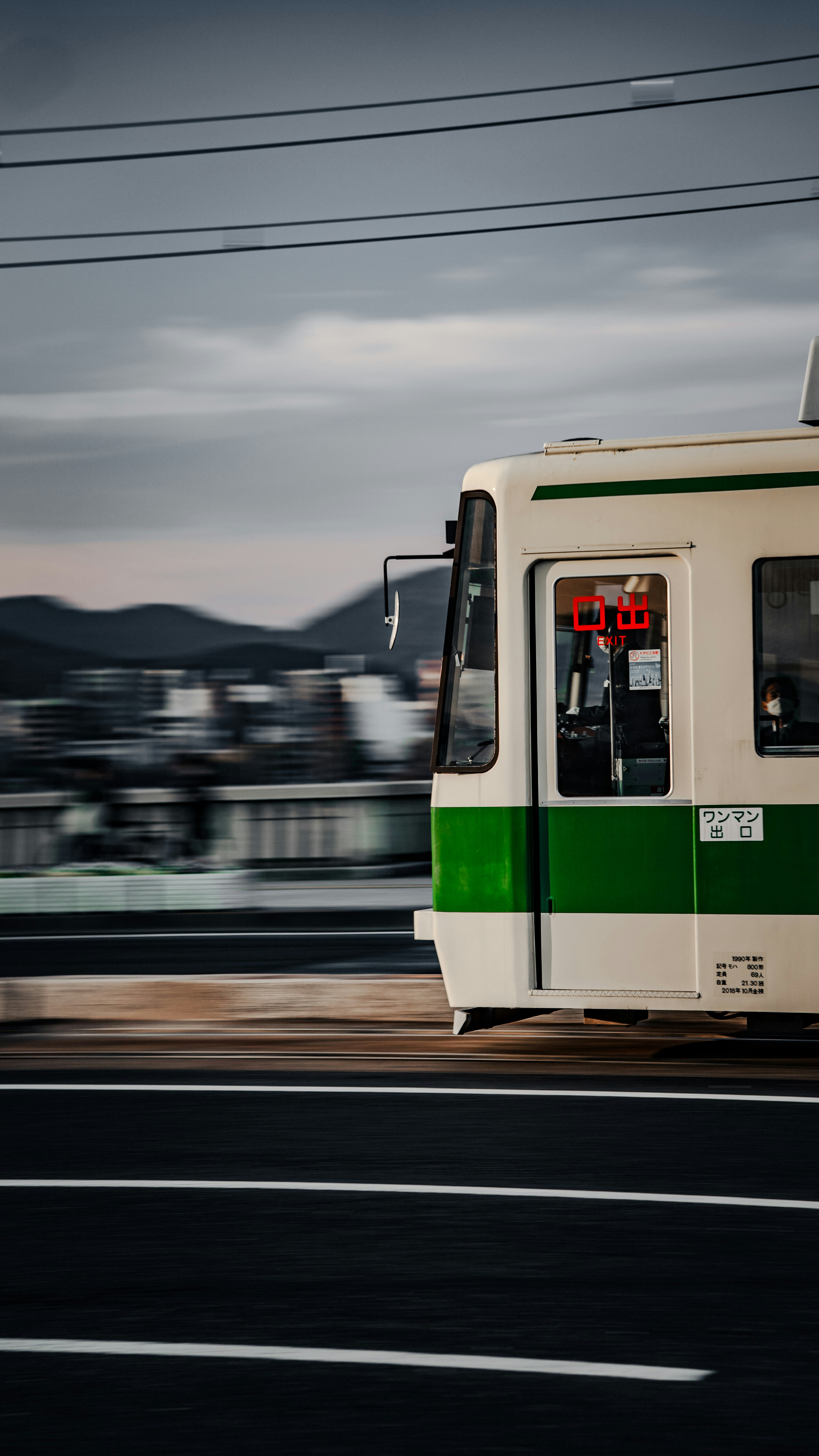 Green-Striped Tram in Motion Across a Quiet Horizon
