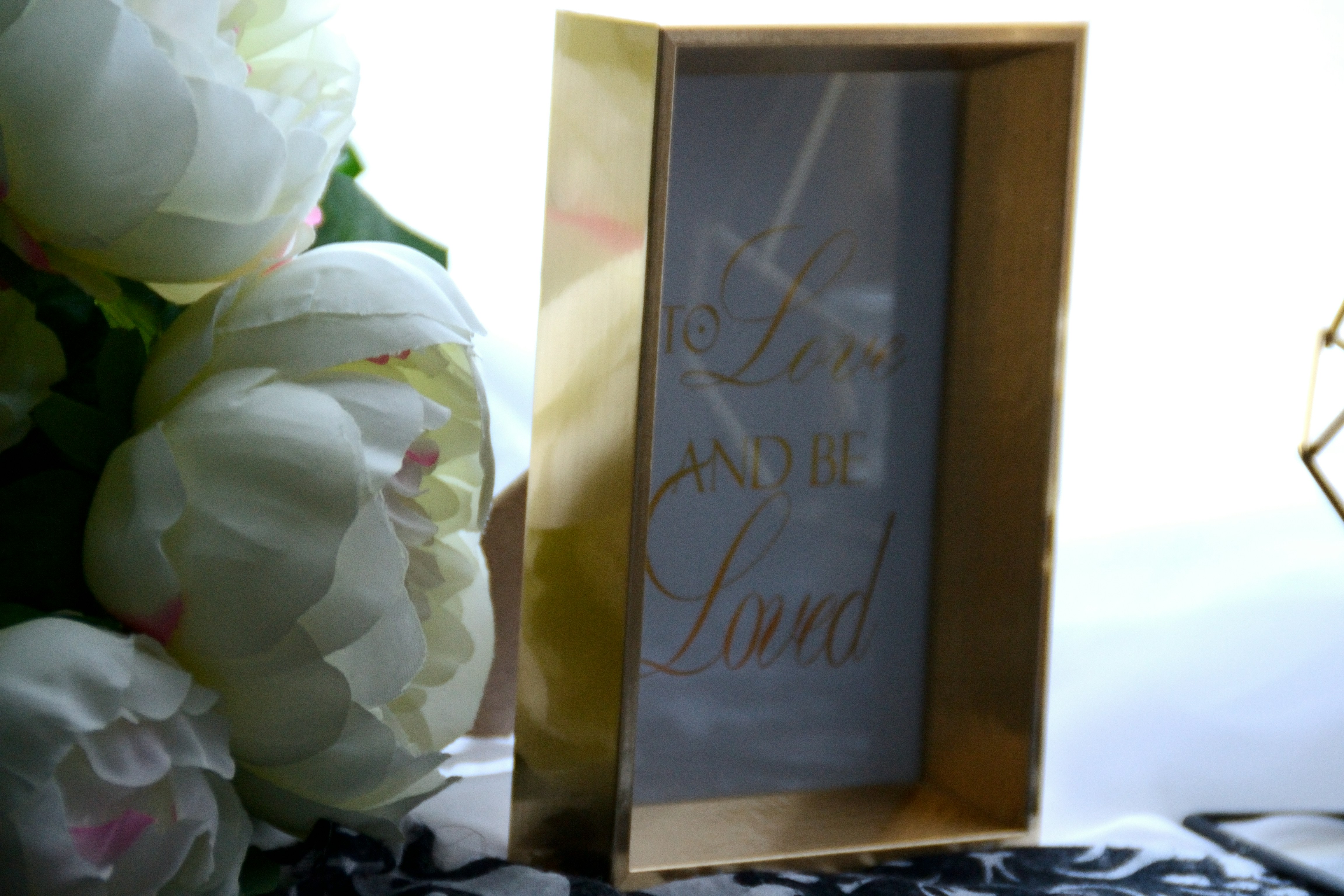 Luminous Frame: A Gold-Toned Keepsake Beside Florals