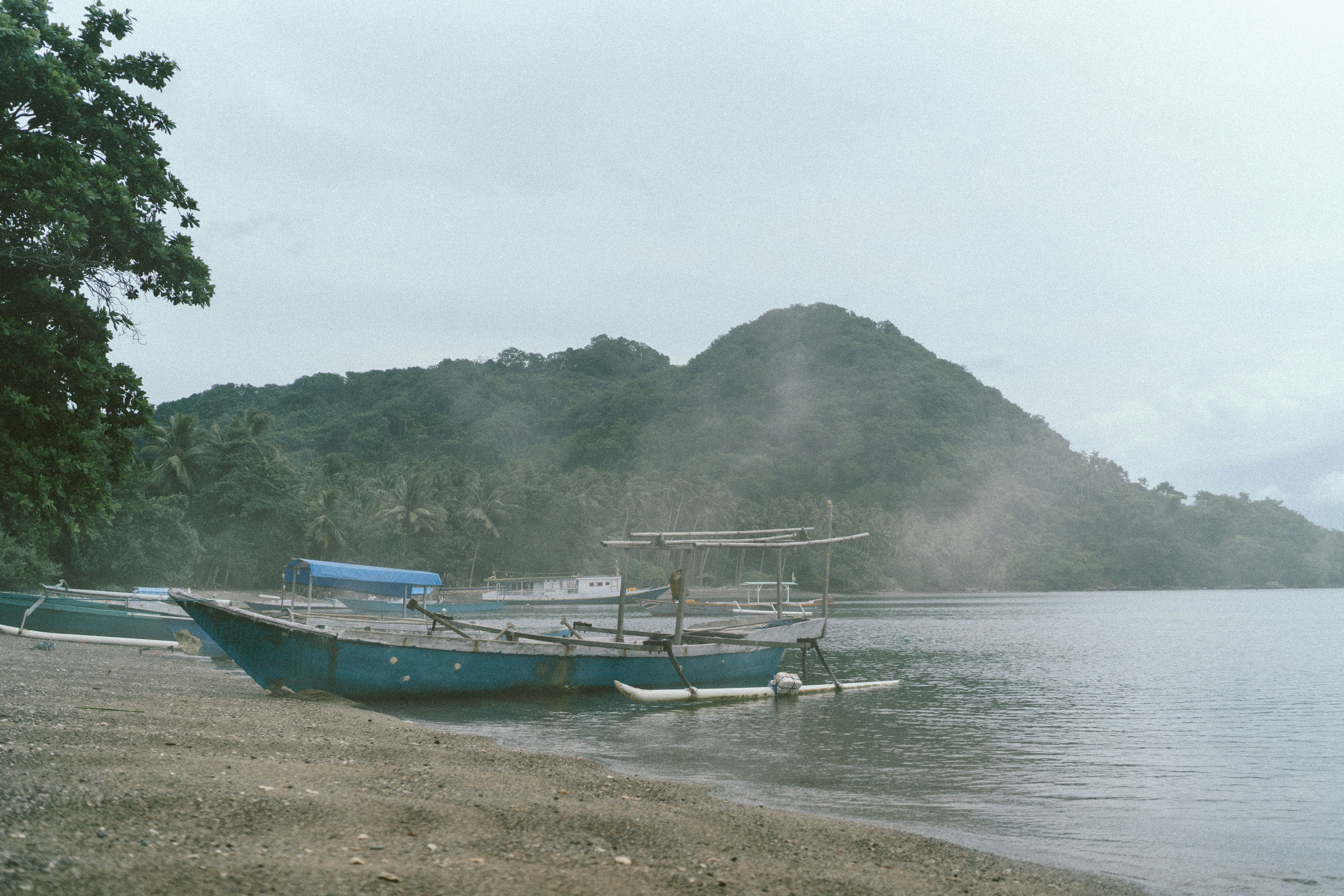 Blue Boat on a Quiet Shore Under Misty Hills