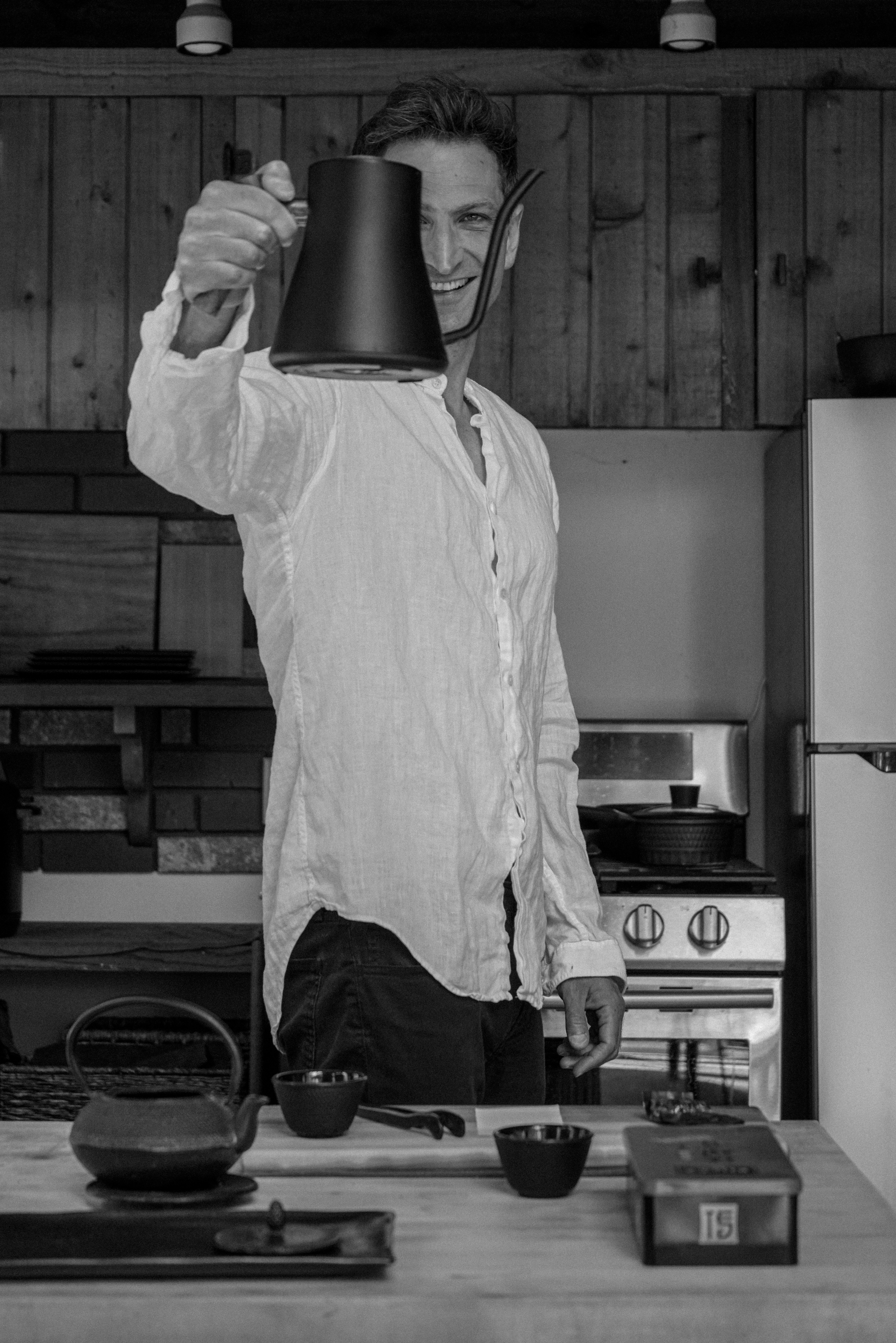 Pouring Presence: A Chef—Mid-gesture in a monochrome Kitchen Moment