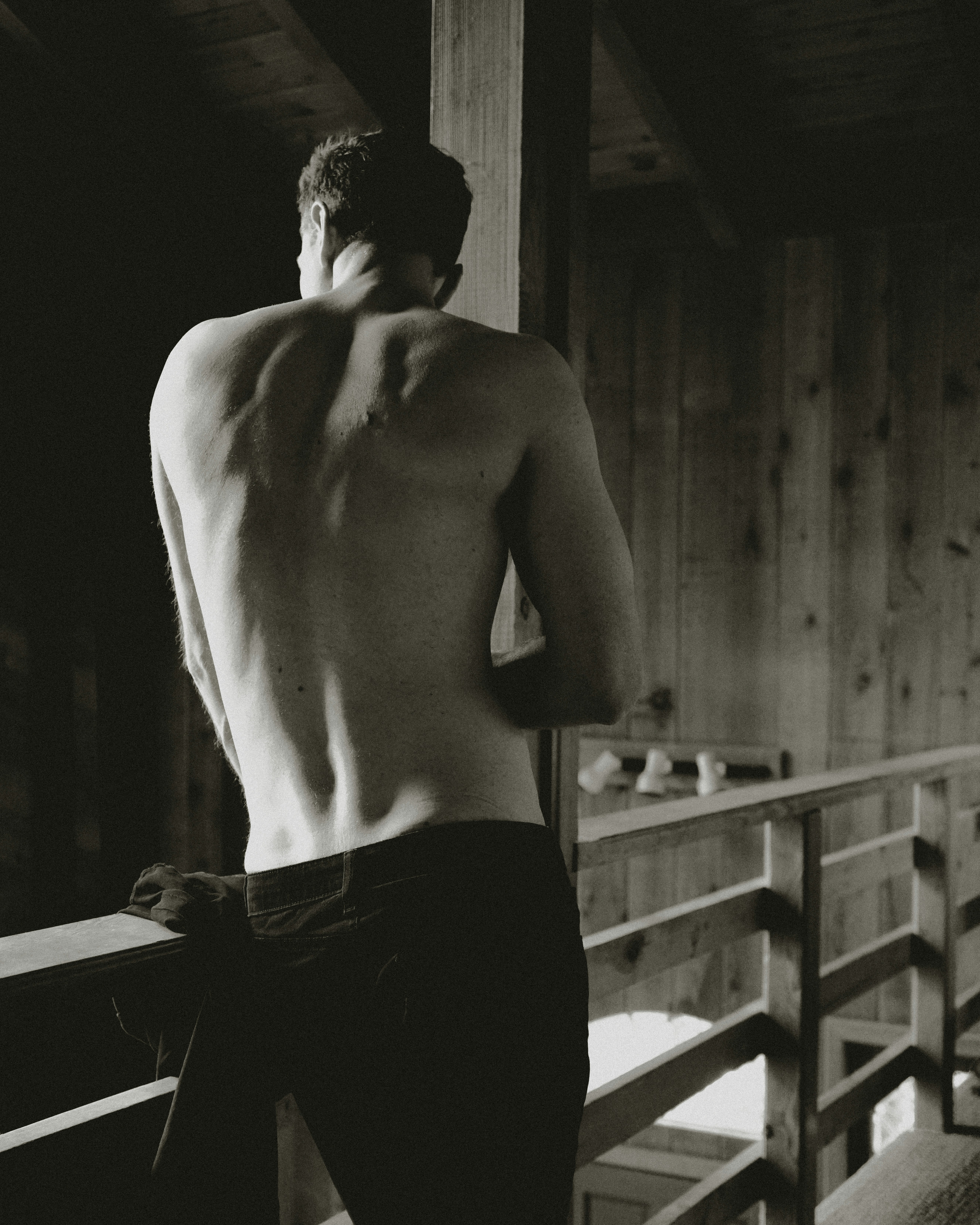 Backlit in Wood: a solitary figure studies the railing