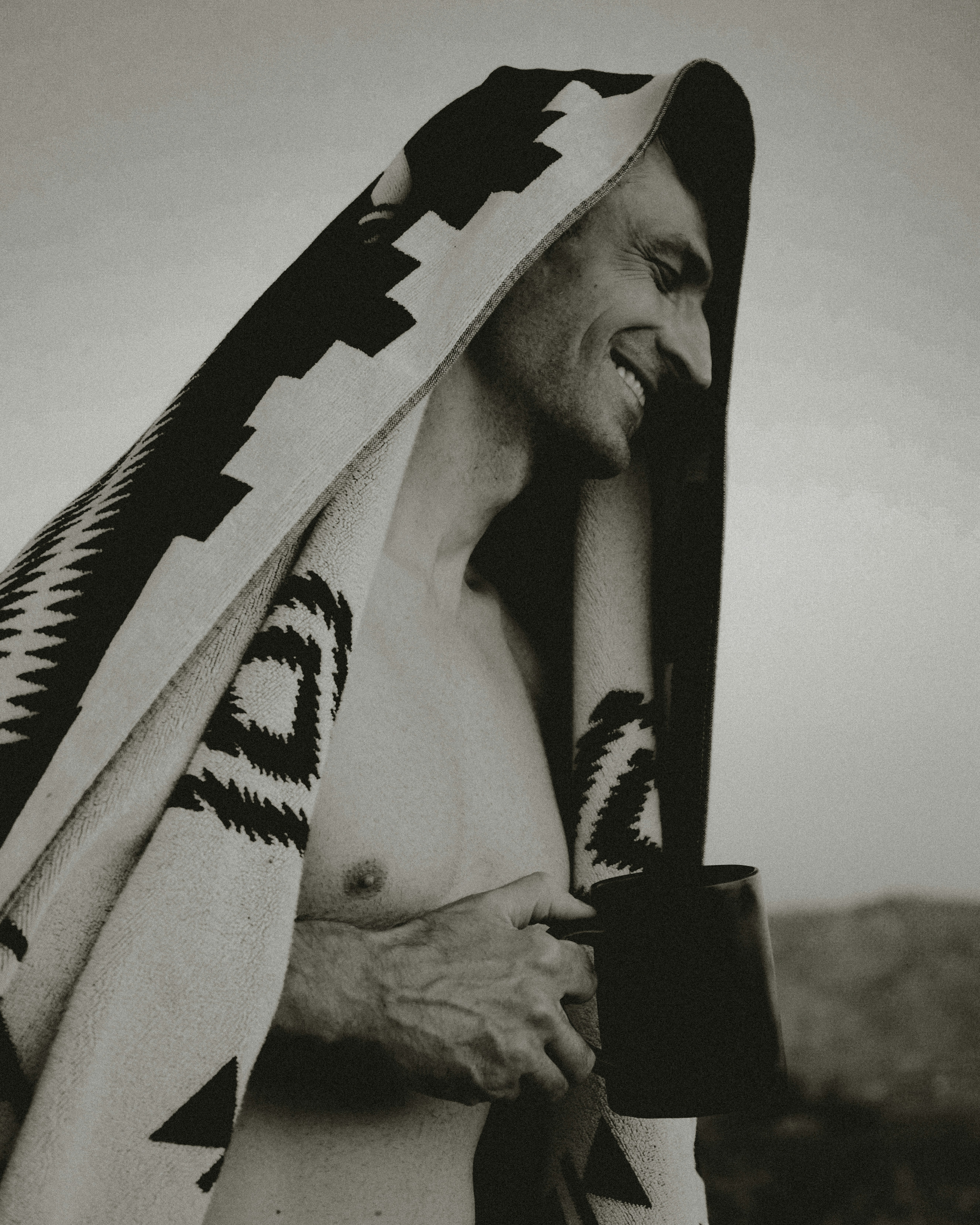 Smiling silhouette beneath a patterned shawl on a windswept horizon