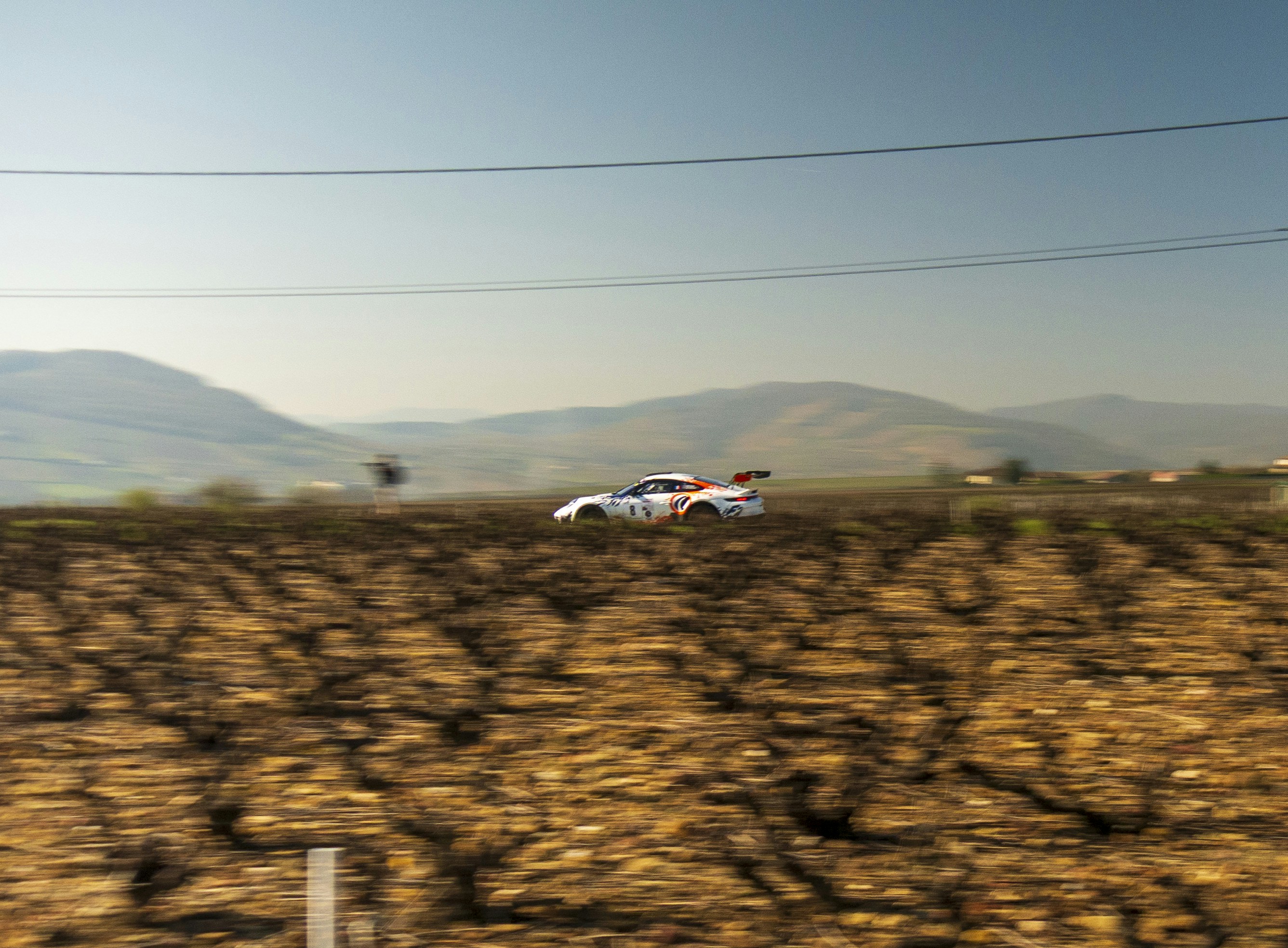 Dusty Sprint: A White Rally Car Flees Across a Field