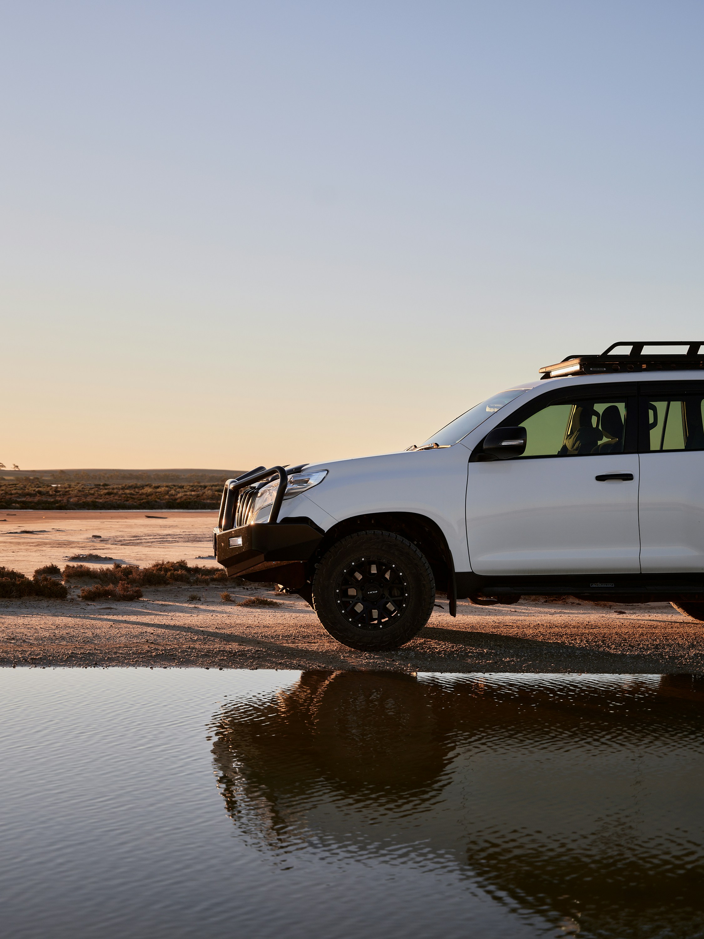 Desert Drive at Dusk: A White SUV Standing by a Glassy Pool