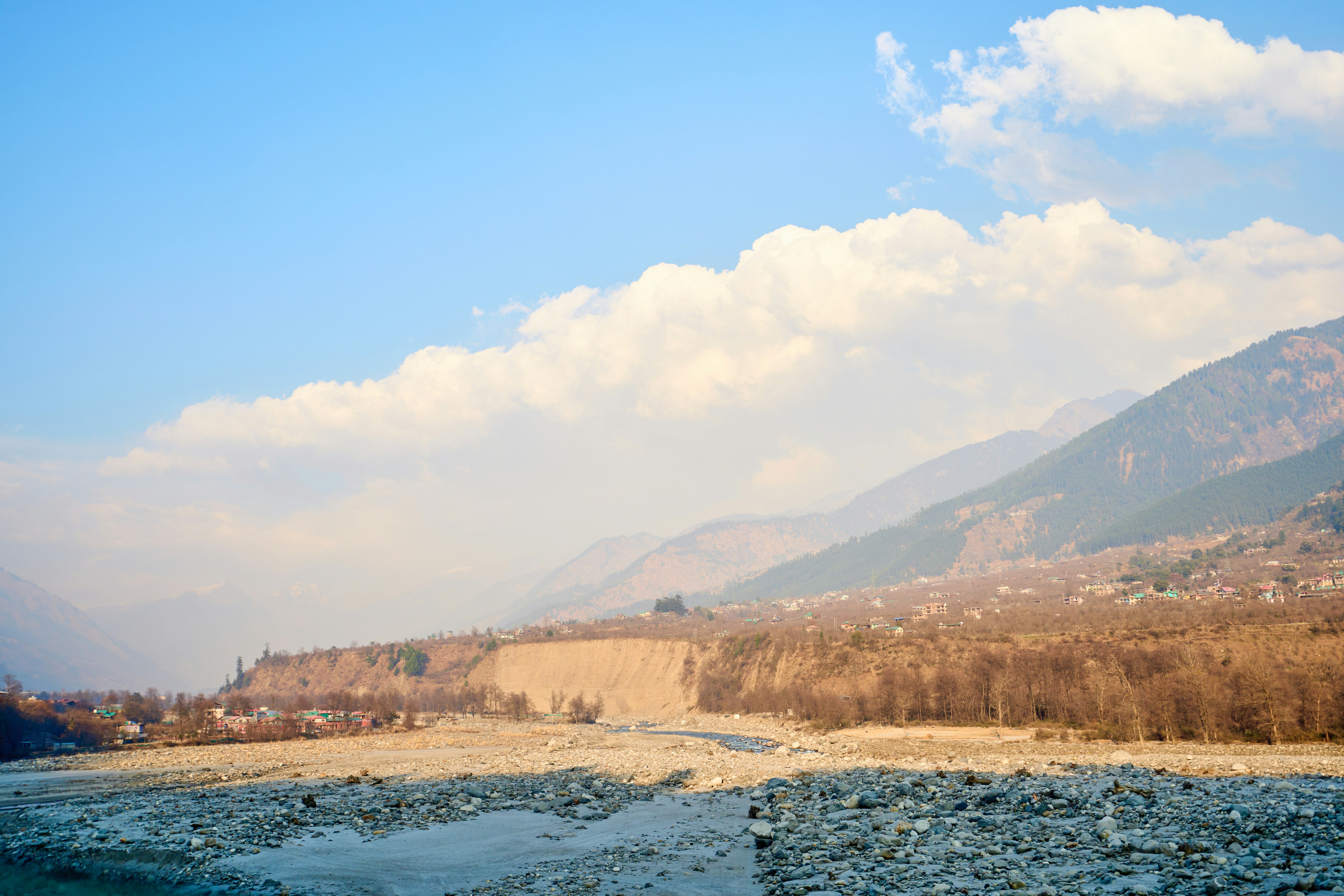 Dusty riverbank beneath a calm sky with distant hills