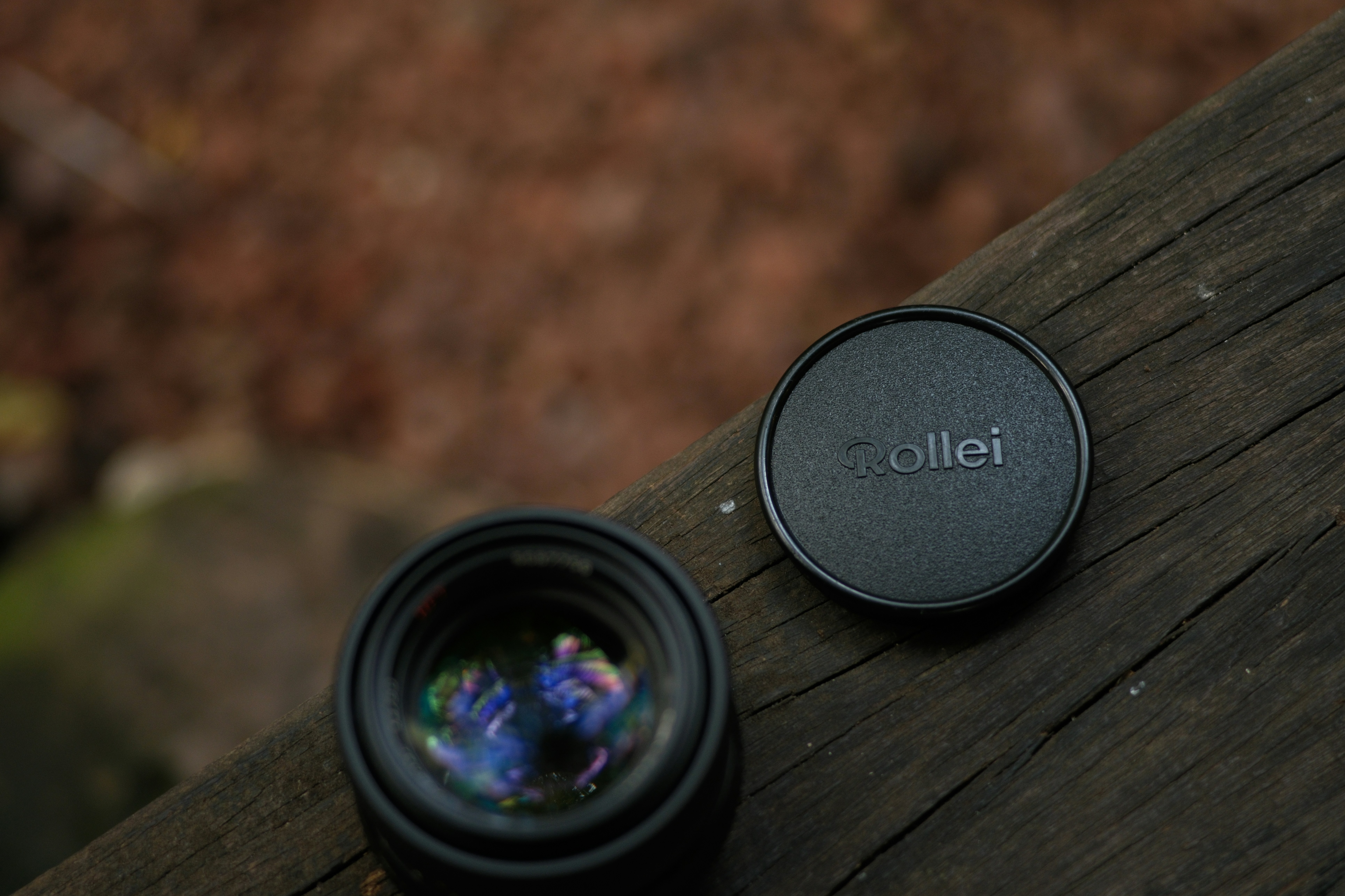 Lens Cap Off: A Rollei Lens Resting on Weathered Wood