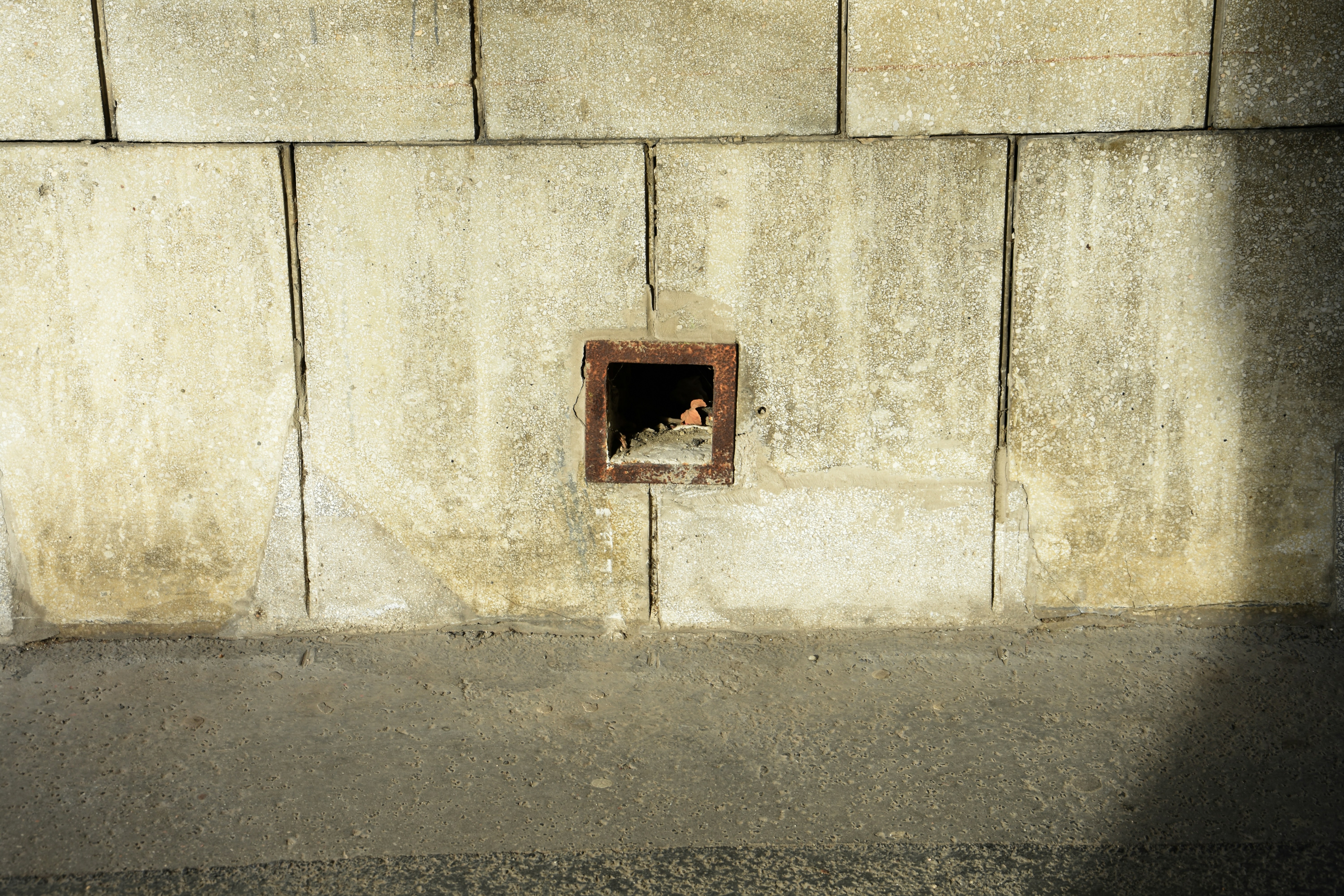 Concrete Wall with Small Vent: Echoes of a Hidden Creature
