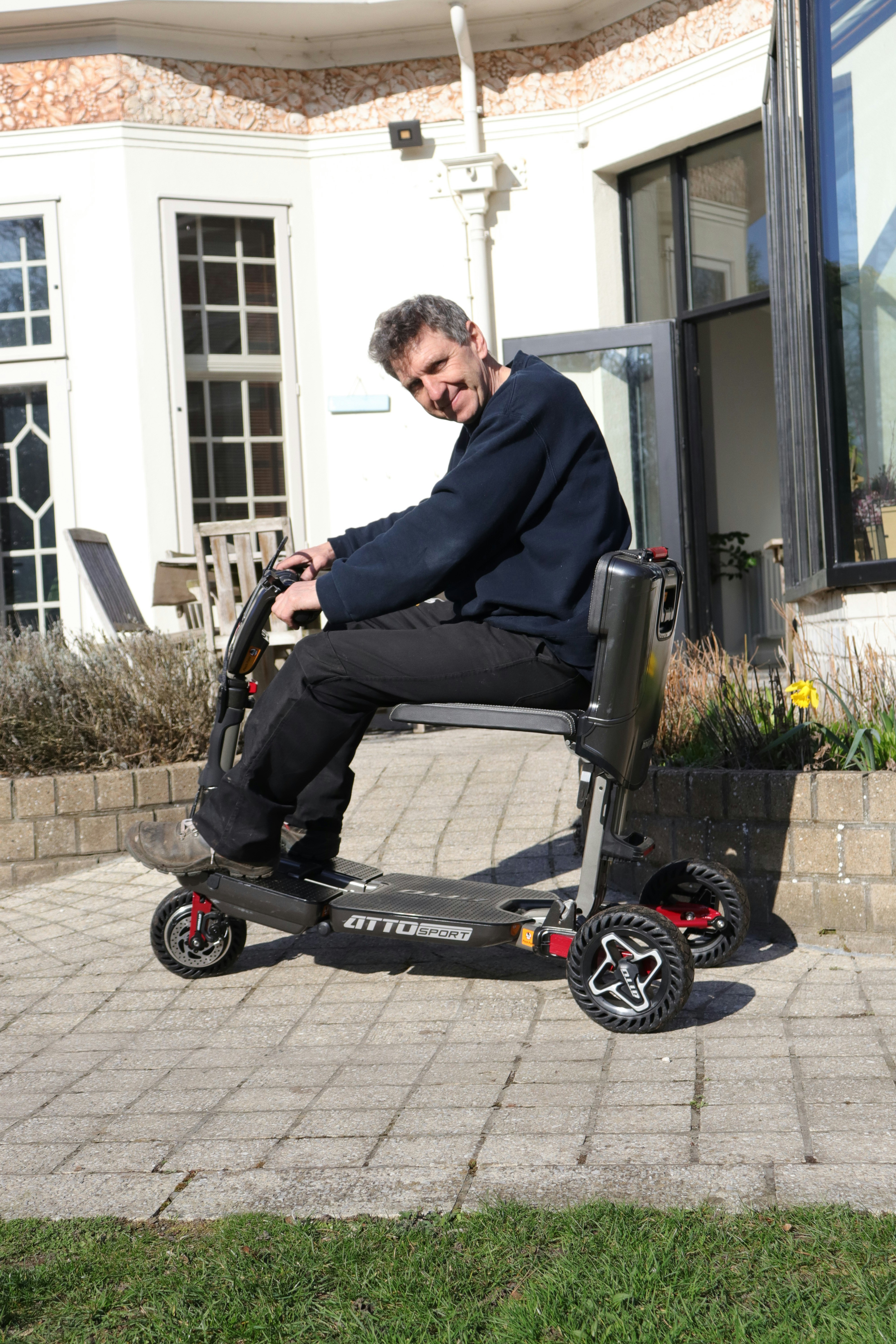 Man on an electric scooter enjoys a sunlit courtyard