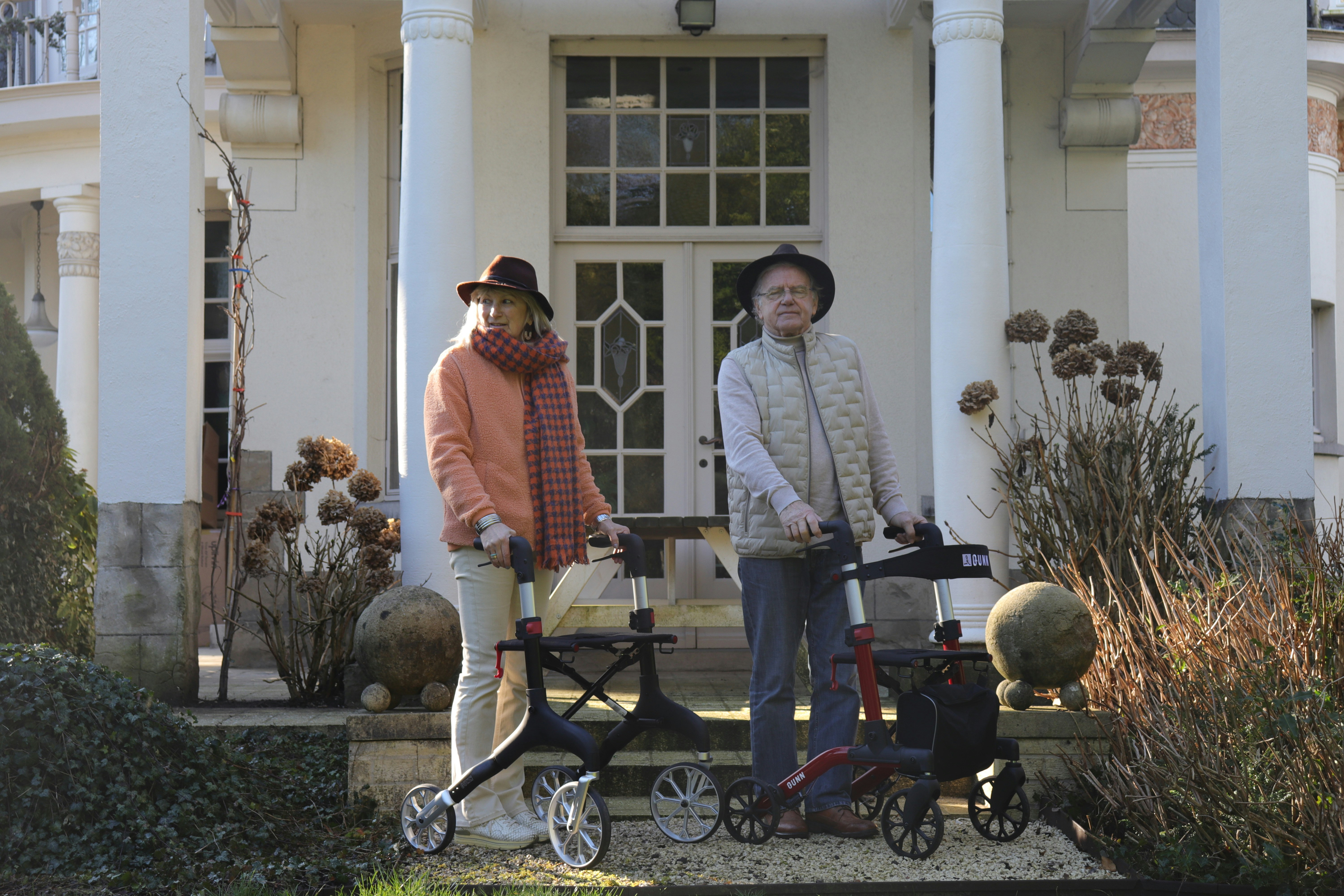 Two Seniors with Mobility Aids Stand Guard Before a Classic Porch