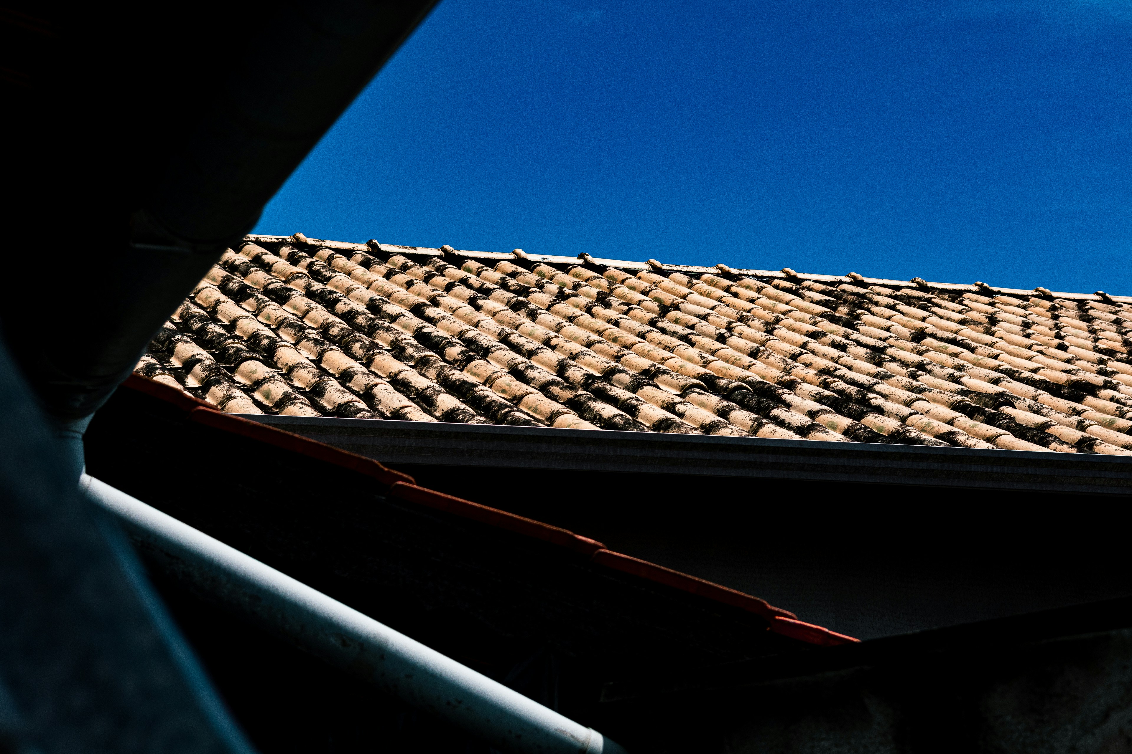 Blue Sky Above Rooftop Tiles and Shadowed Eaves