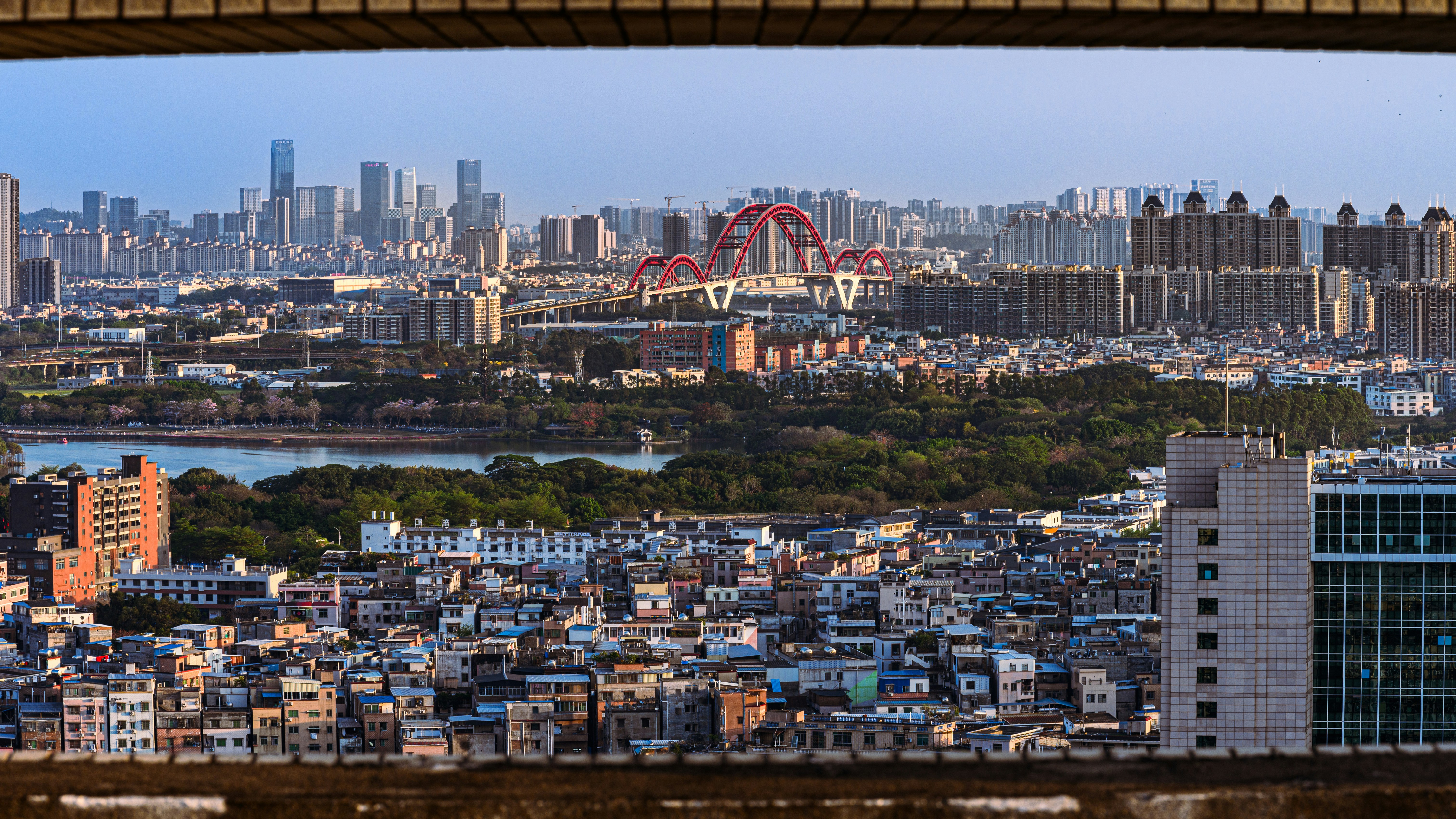 Cityscape Frame: A Red Arch Bridge Framing a Dense Riverside Quarter