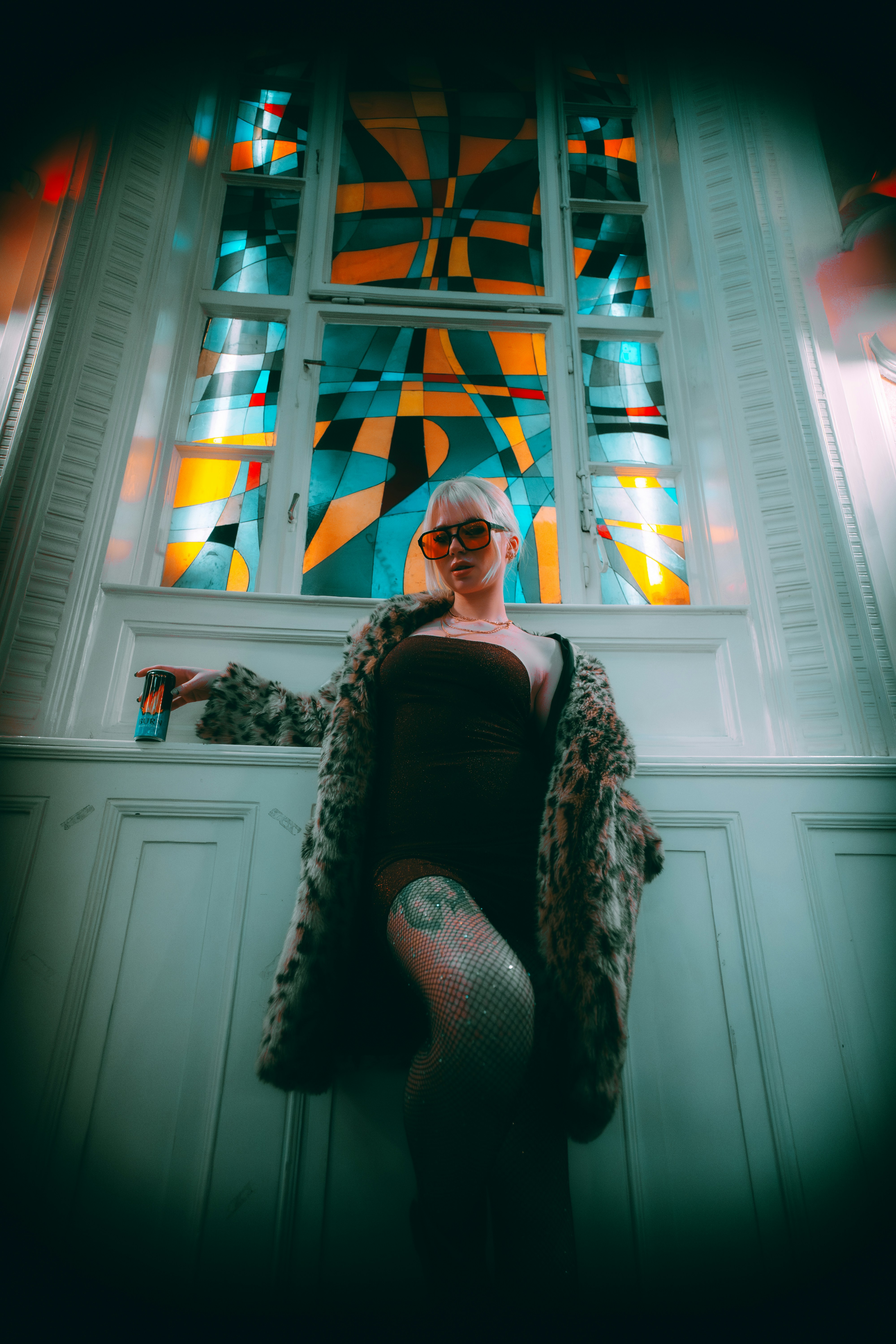 Woman in leopard coat poses by stained glass window