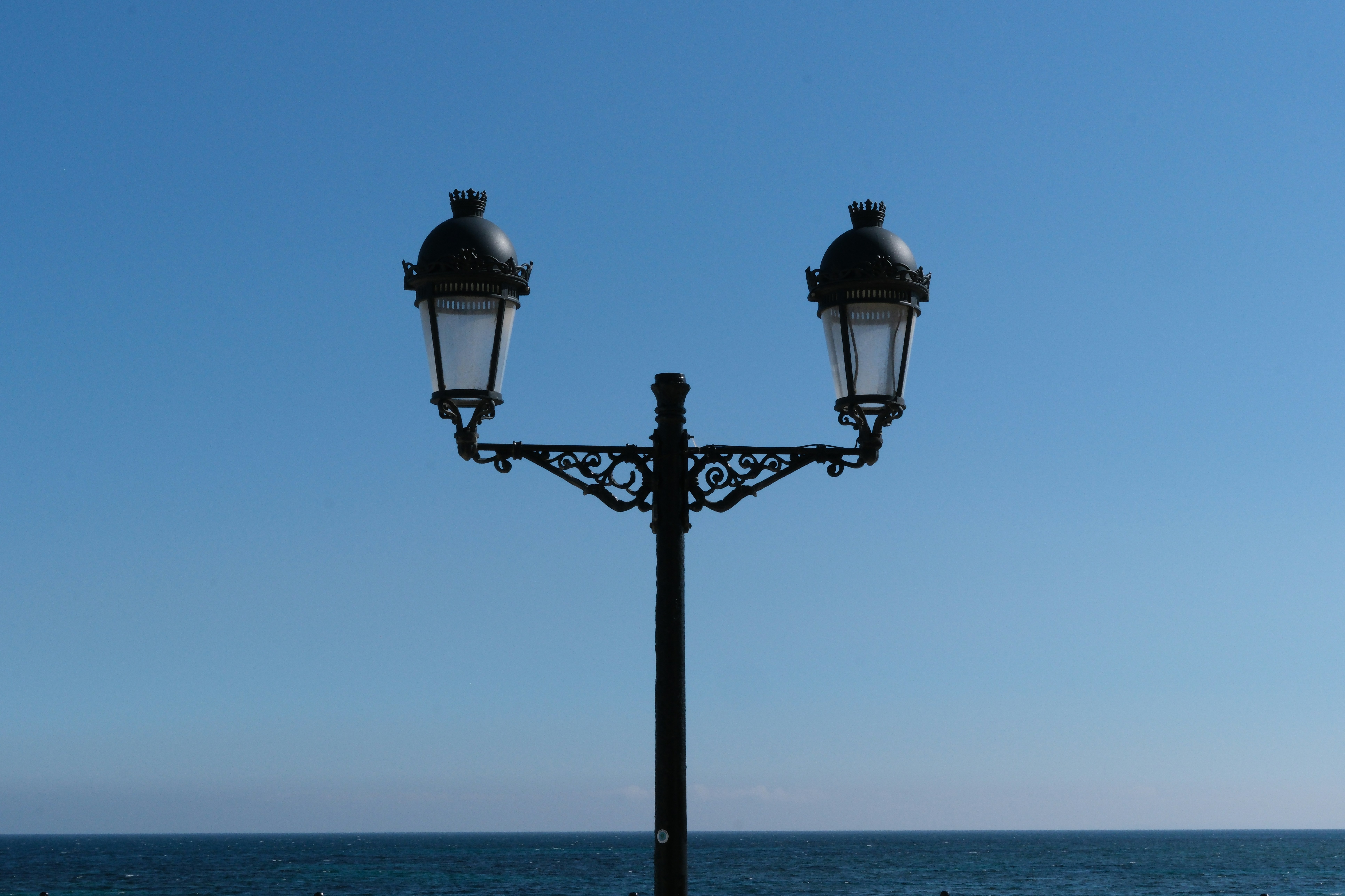 Seaward Lanterns: A Lone Pier-Top Lamp Against the Ocean Horizon