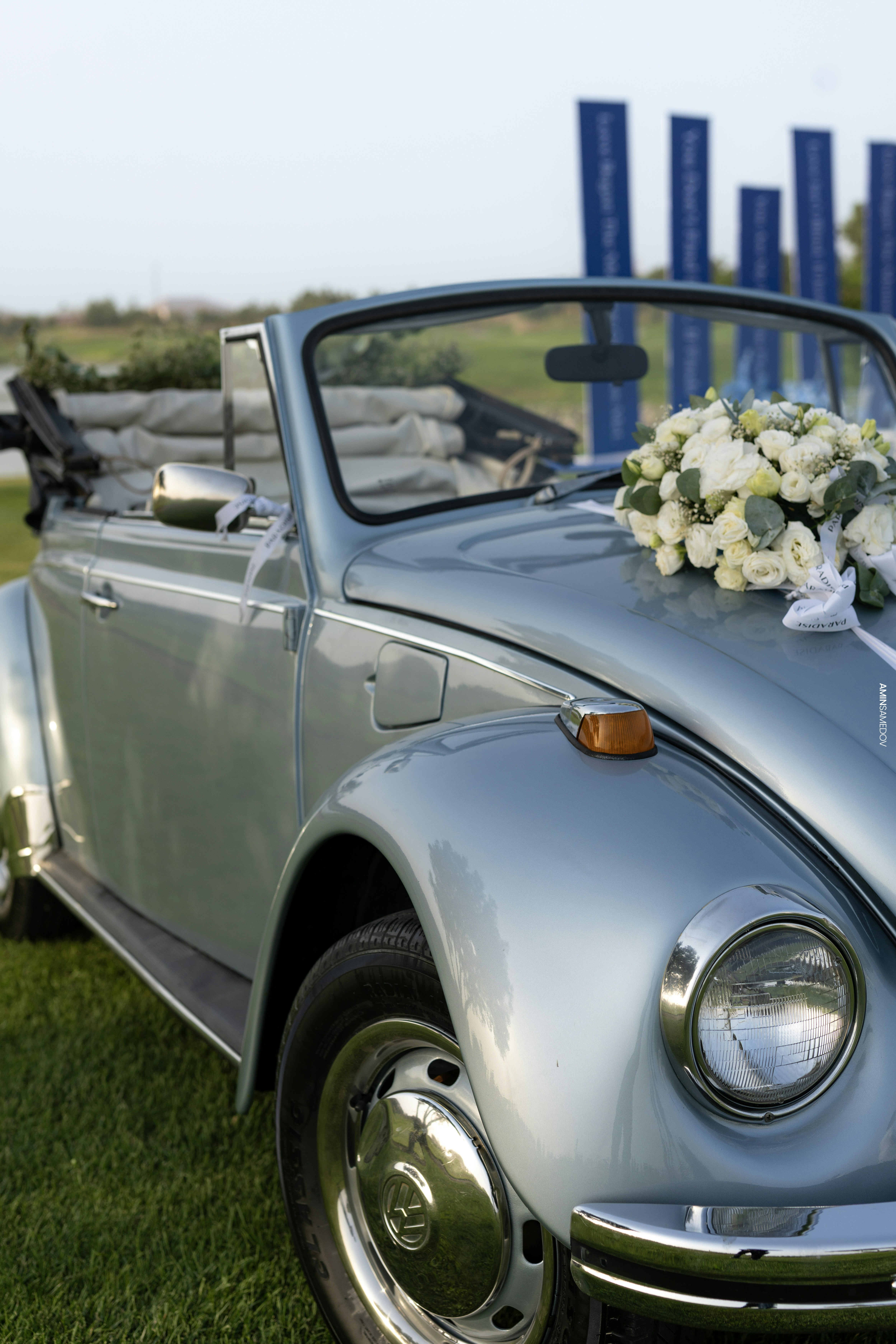 Blue Vintage Convertible adorned with a wedding bouquet at an outdoor ceremony