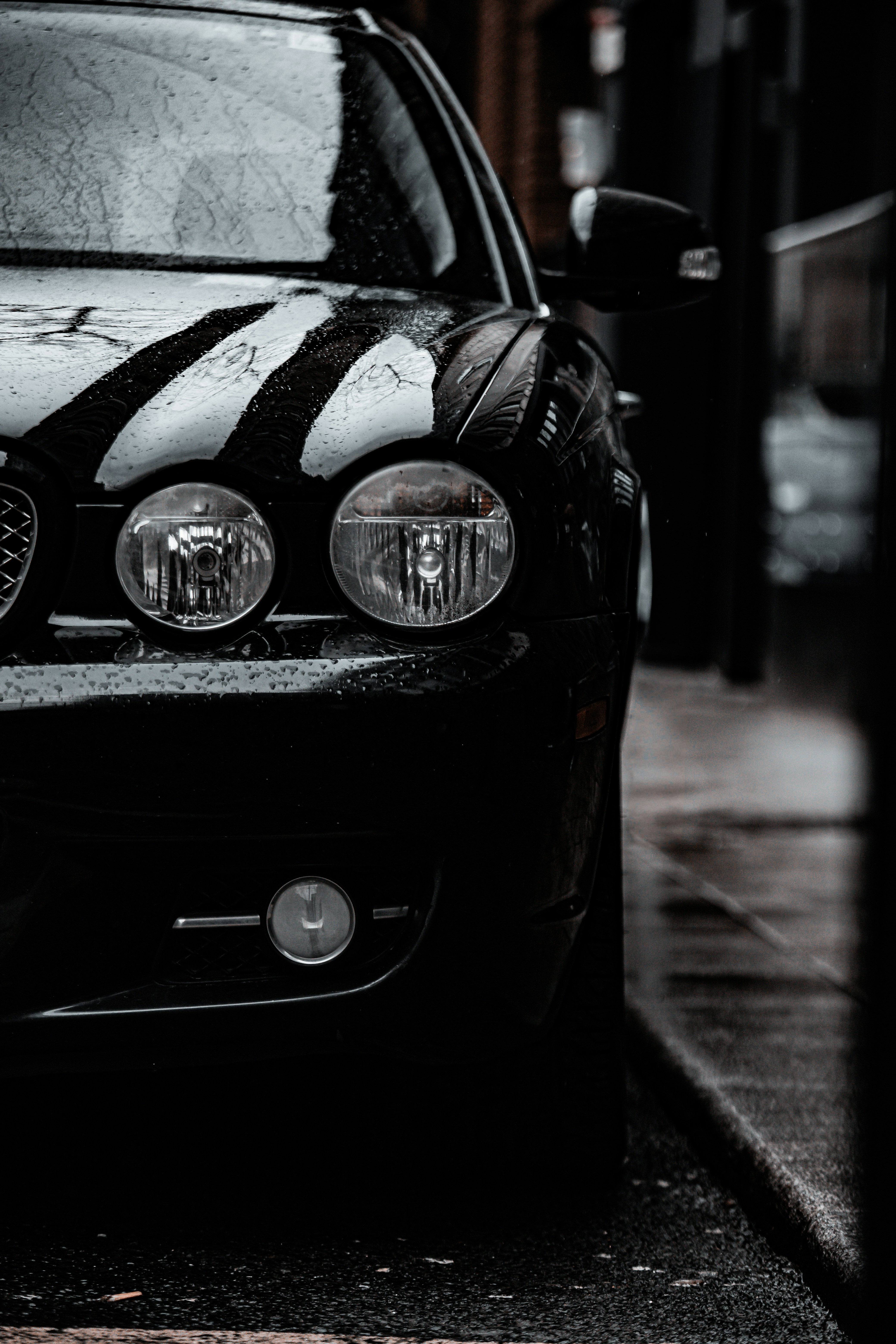 Rain-Slicked Grille: A Car’s Quiet Stare Between Streetlights