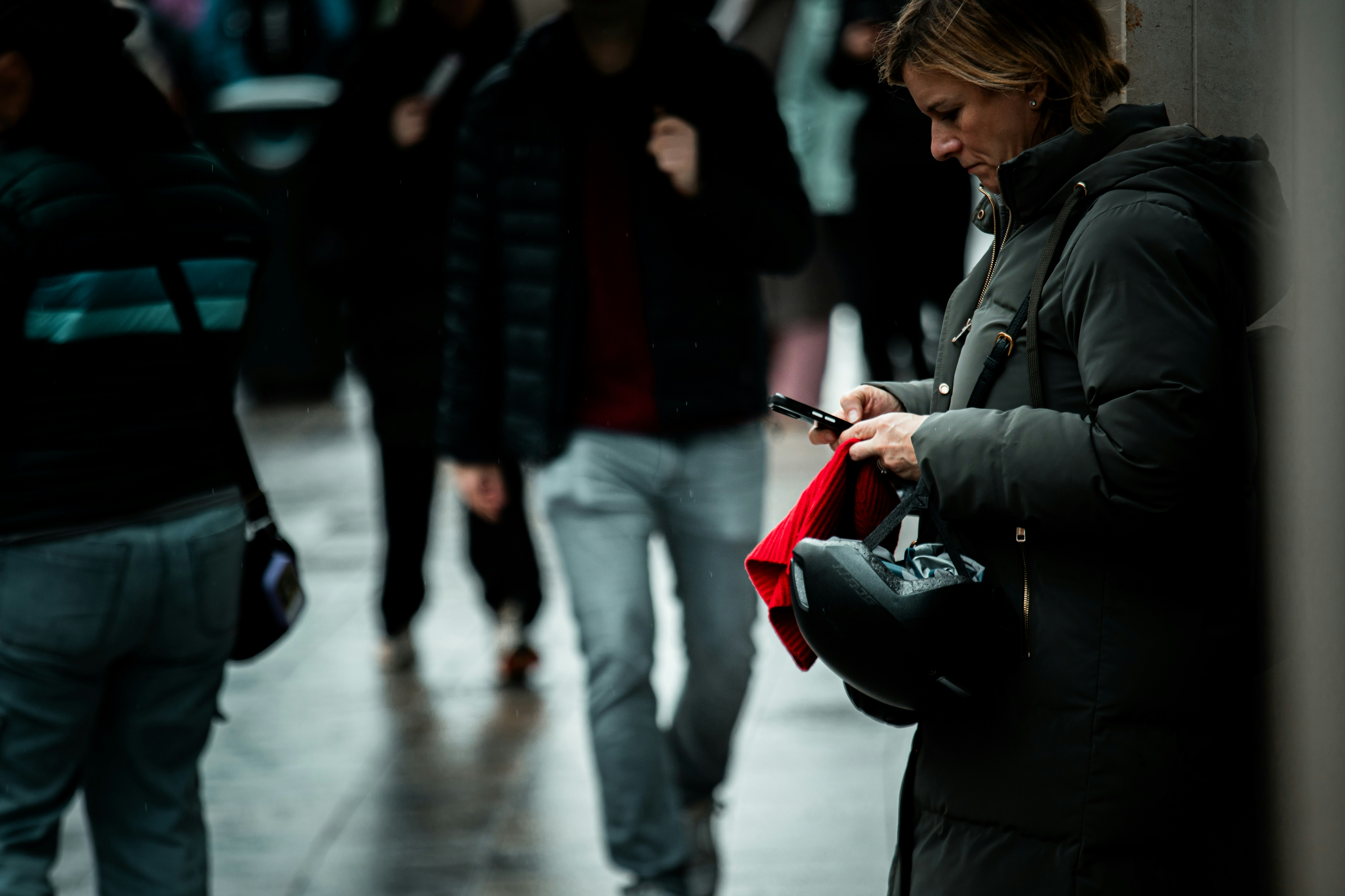 Focused in a Quiet Moment: A Woman Checks Her Phone Amid Urban Flow