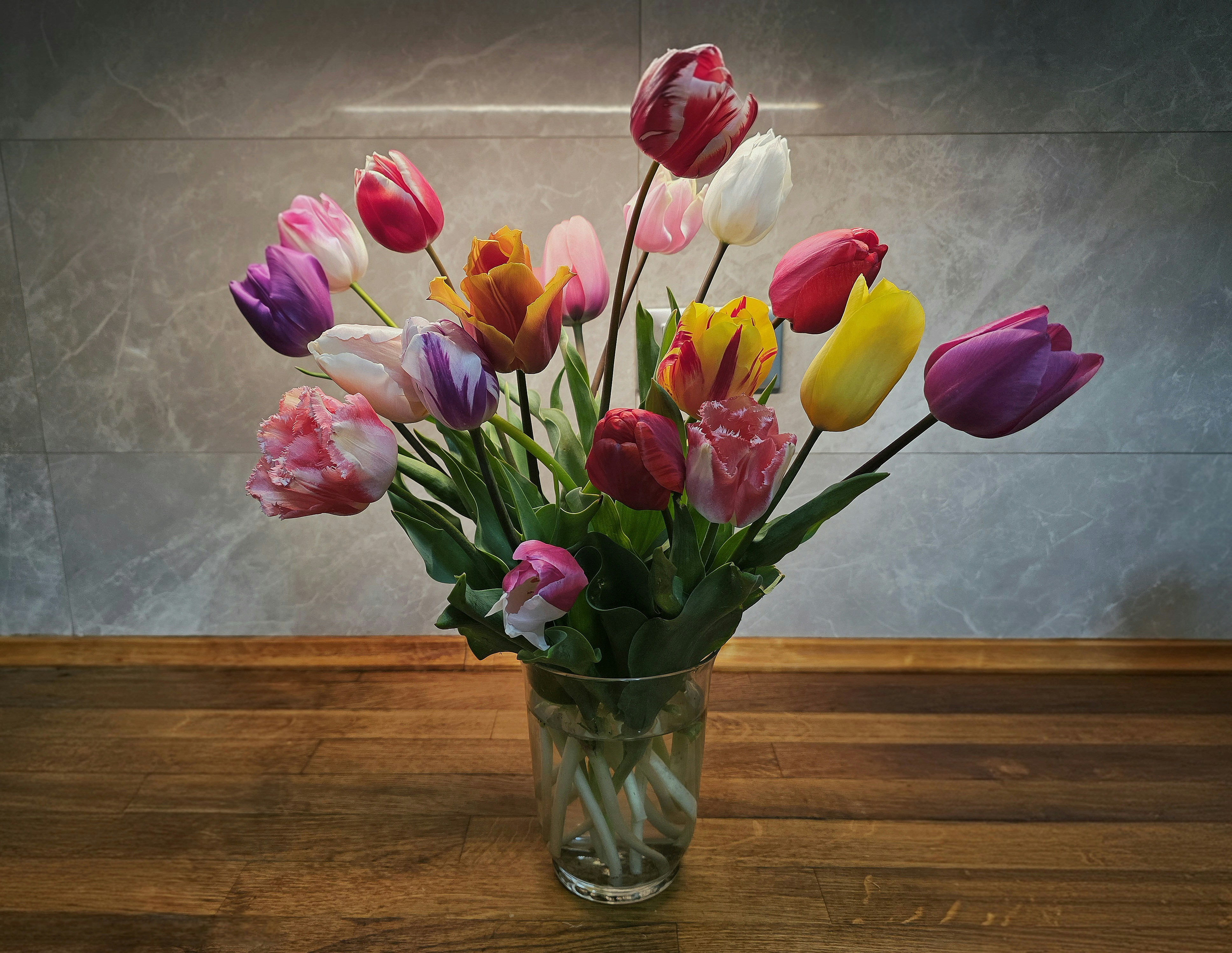 Vibrant Tulip Ensemble in Glass Vase on Warm Wooden Table