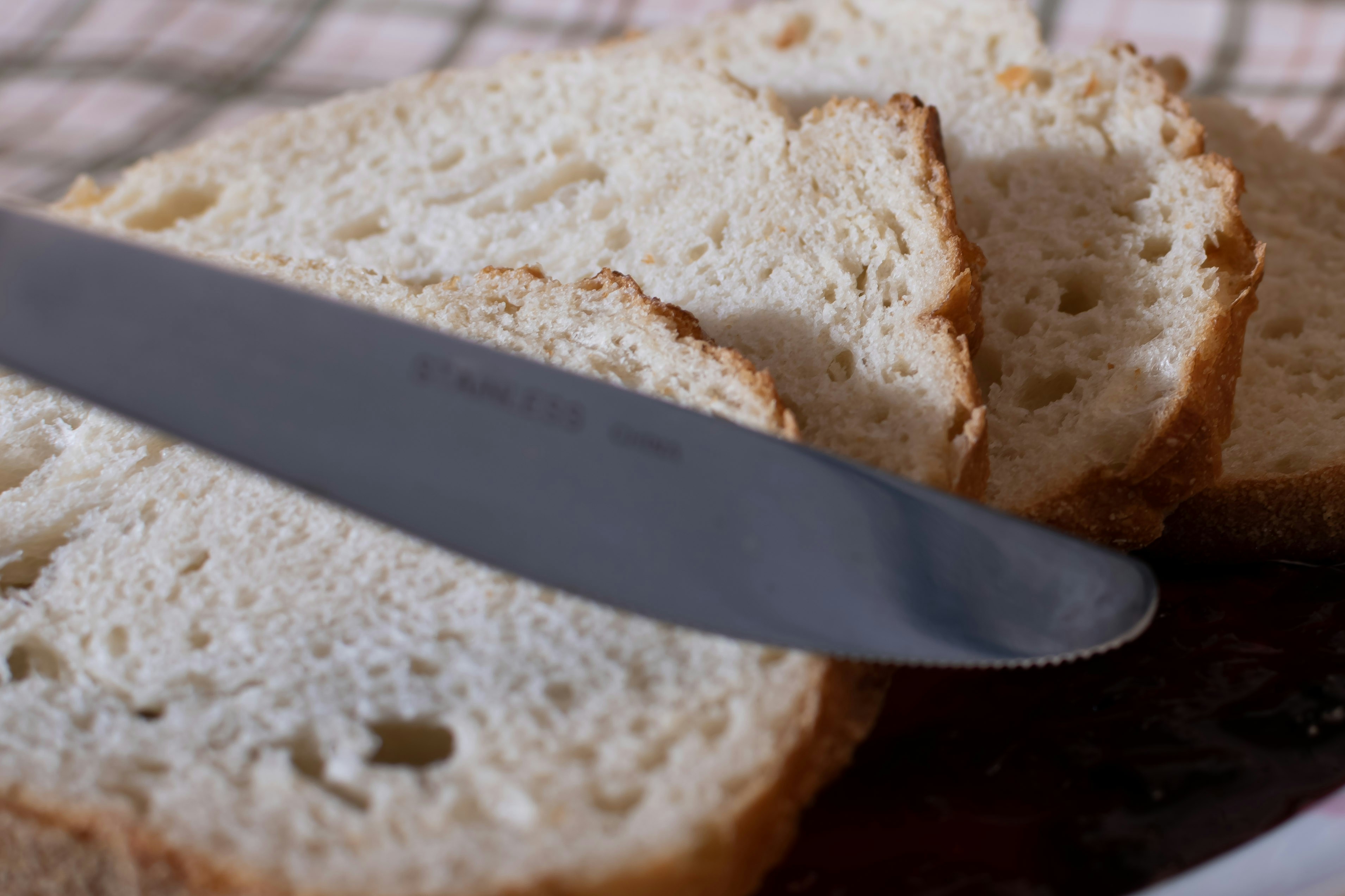 Sliced loaf with a buttered crust and a knife resting across the slices, capturing a rustic bread moment.