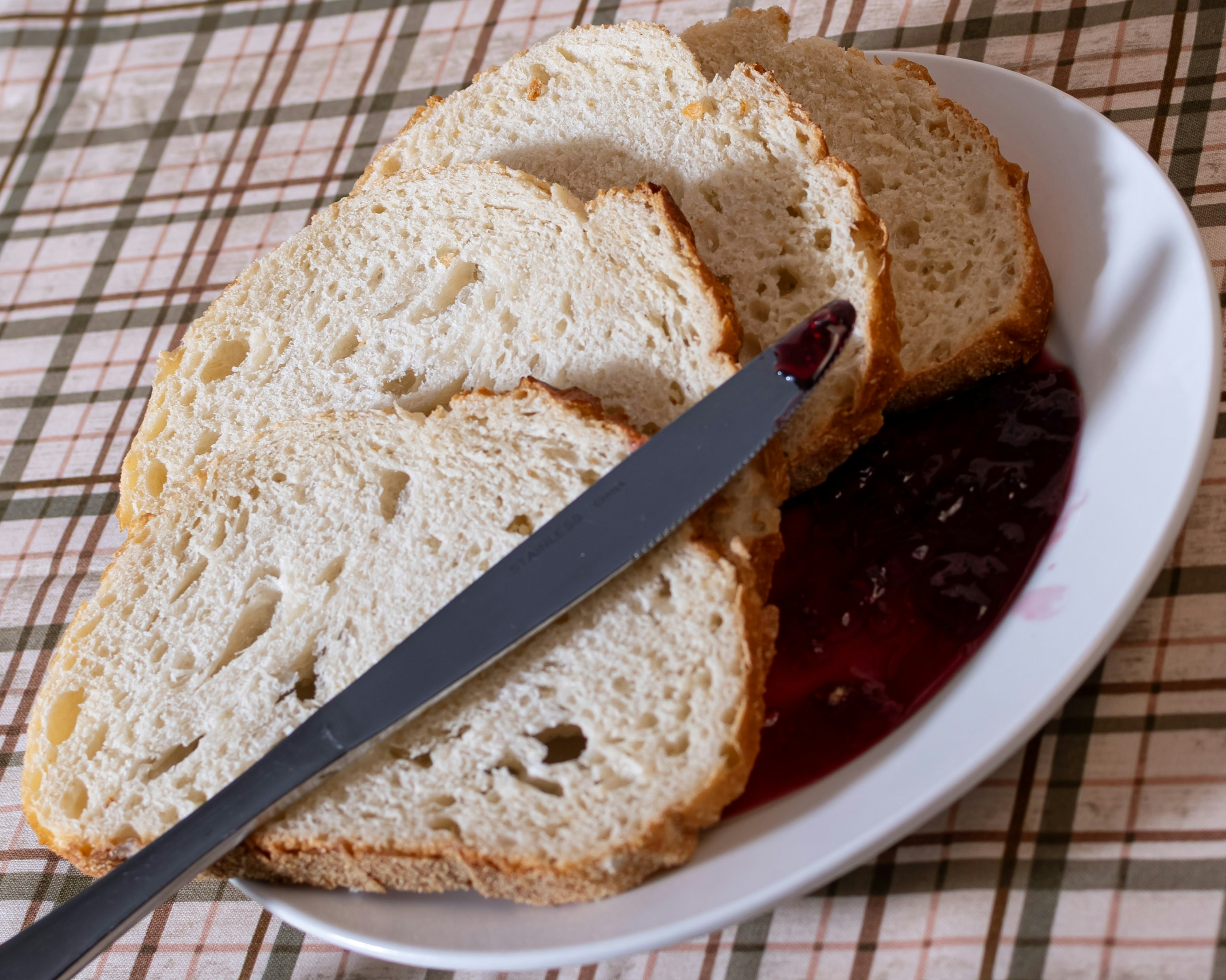 Slice of Quiet Comfort: Bread, Knife, and Jam on a Checkered Table