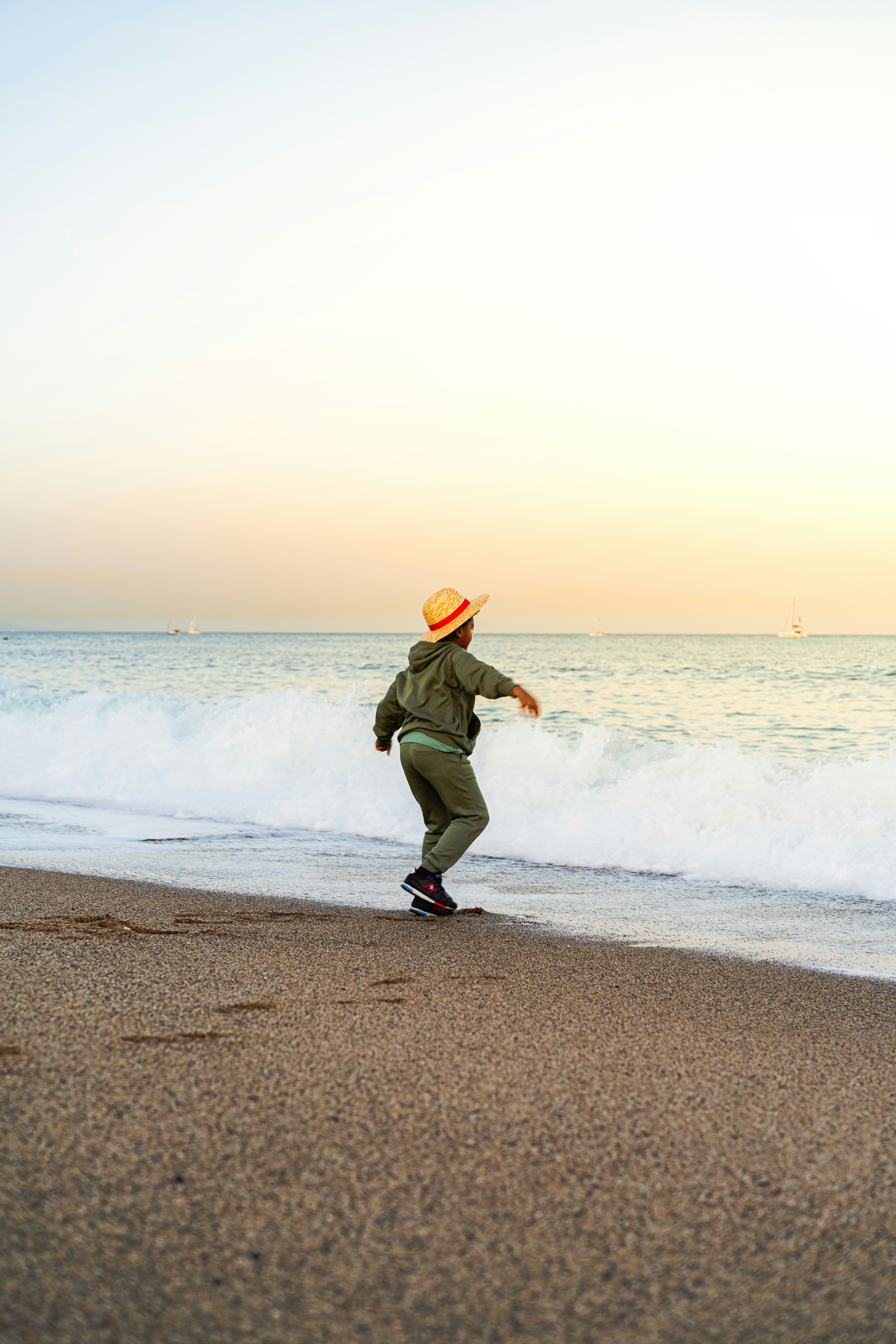 Sunlit Coastal Shuffle: A Child in olive on the shoreline