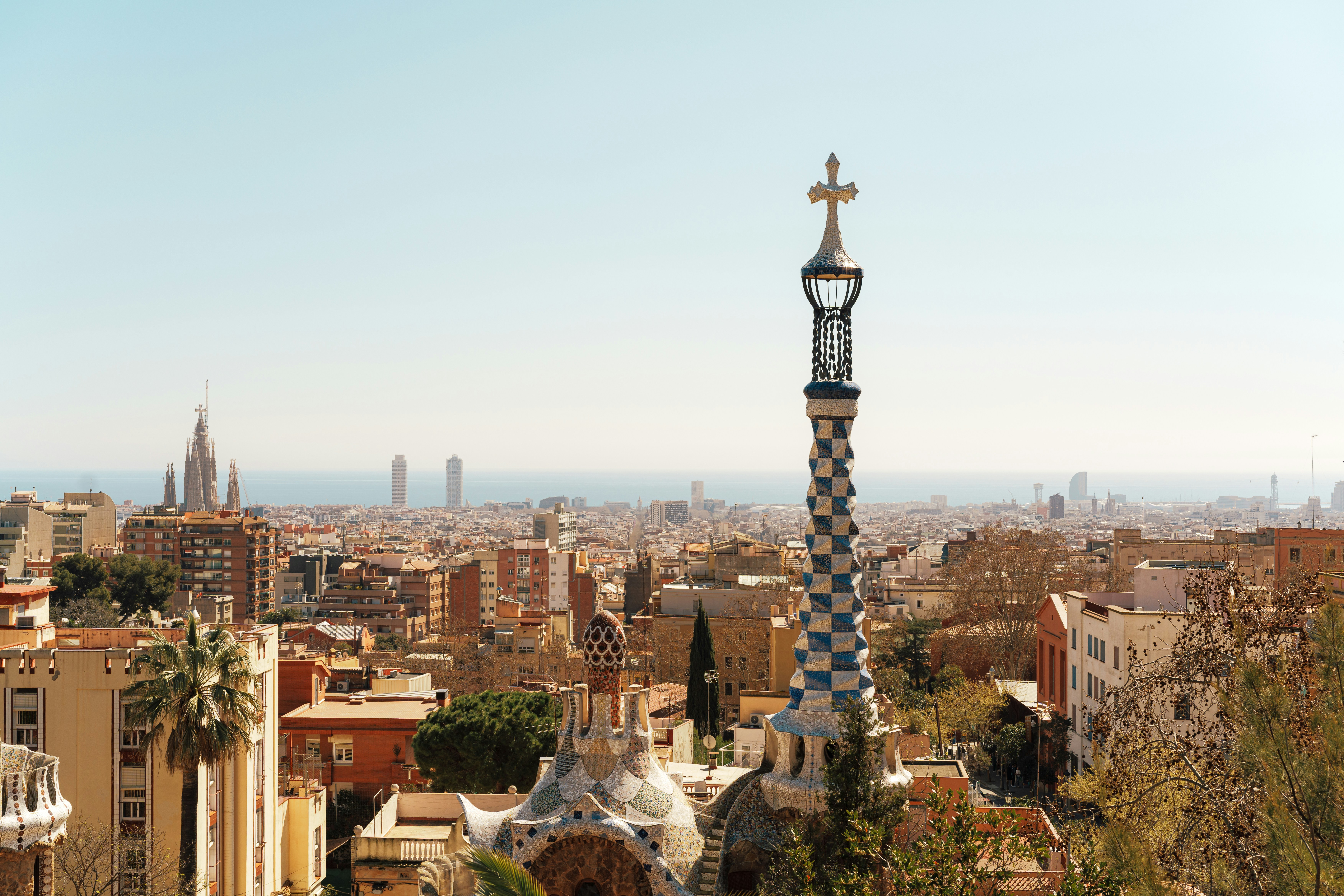 Spire of Park Güell Rising Over Barcelona Rooftops