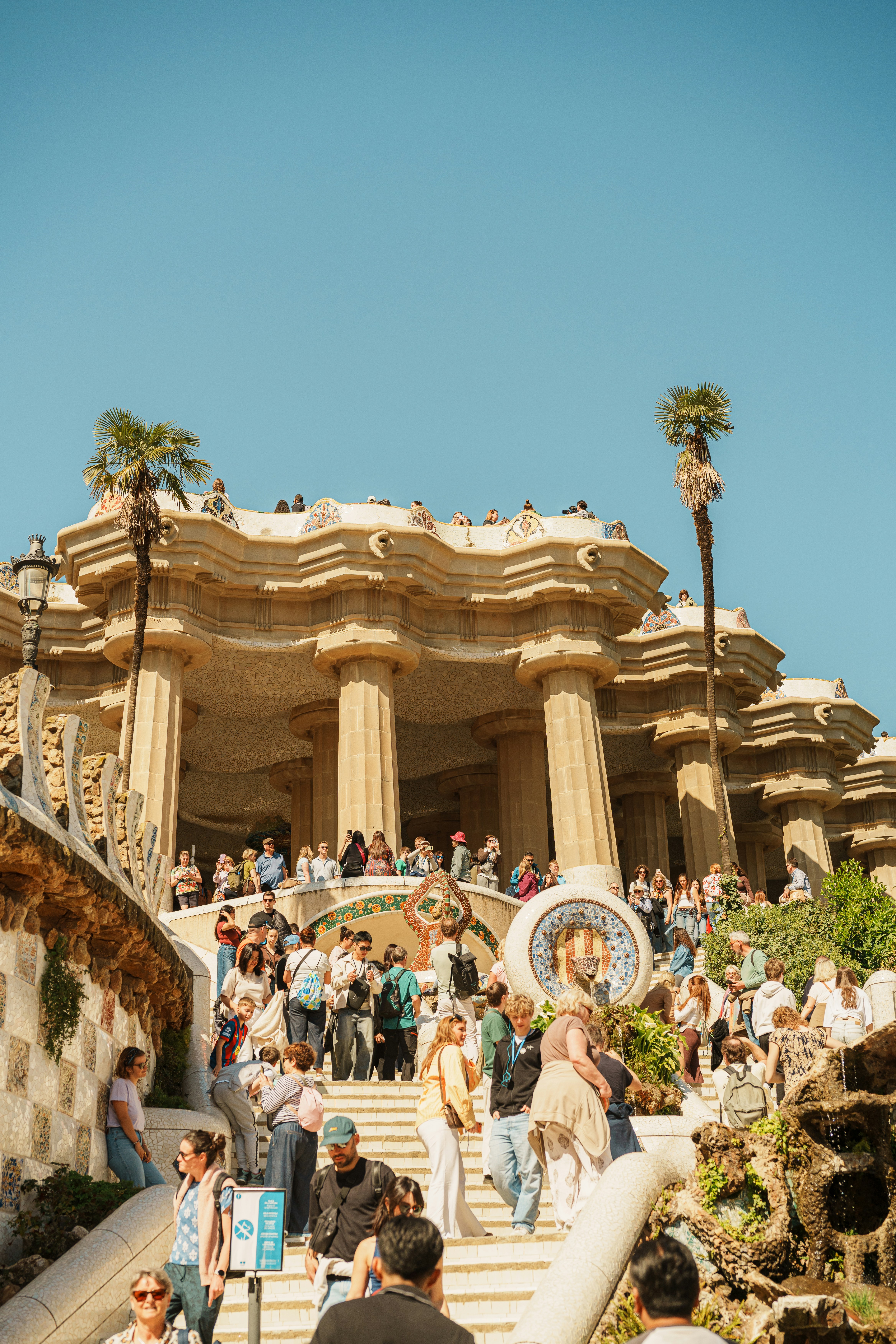 Dramatic Plaza at Parc Güell: Sunlit Columns and Crowds Beneath Ornate Canopies