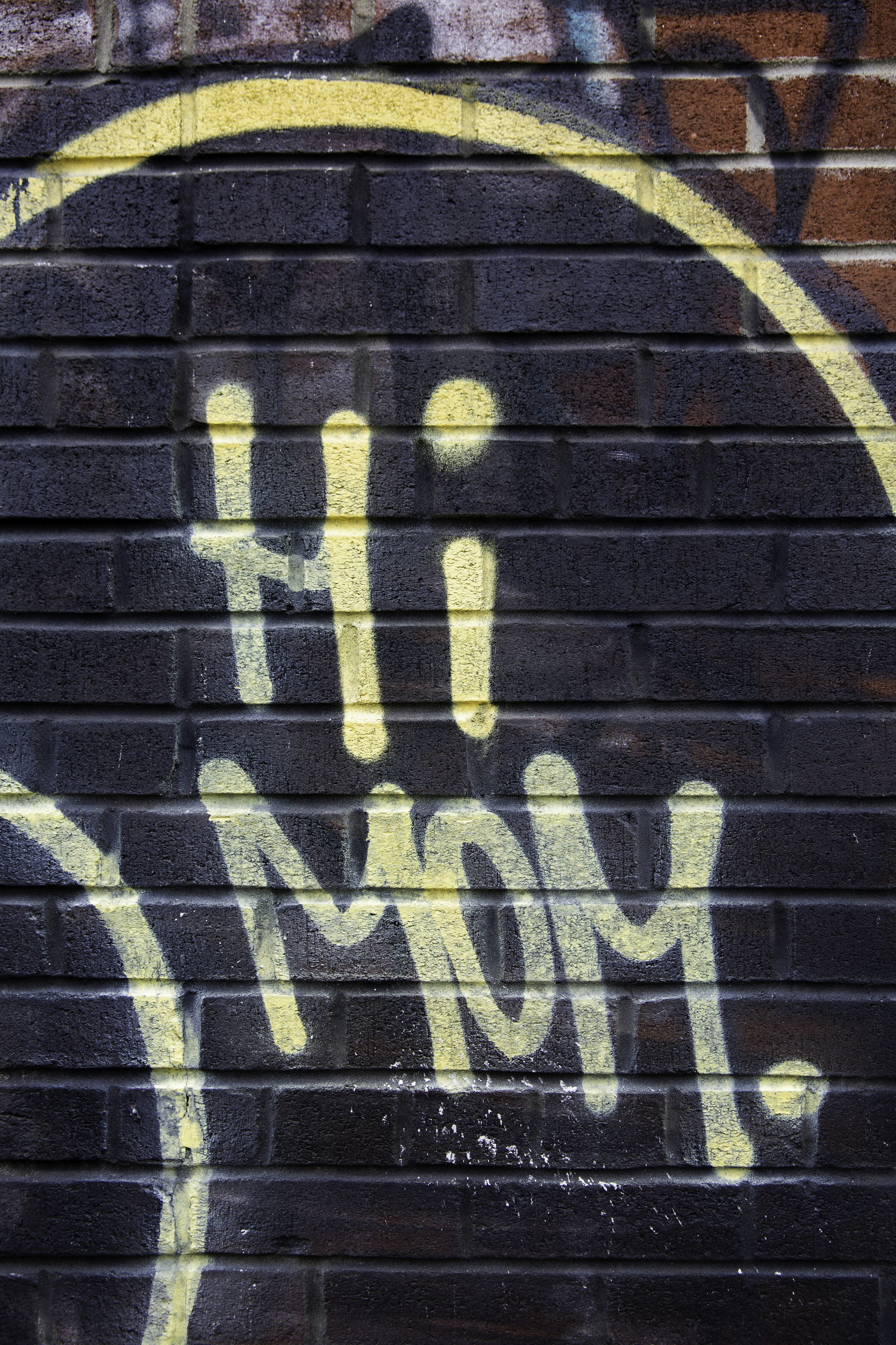 Yellow Graffiti Handprint Graphic on Dark Brick Wall