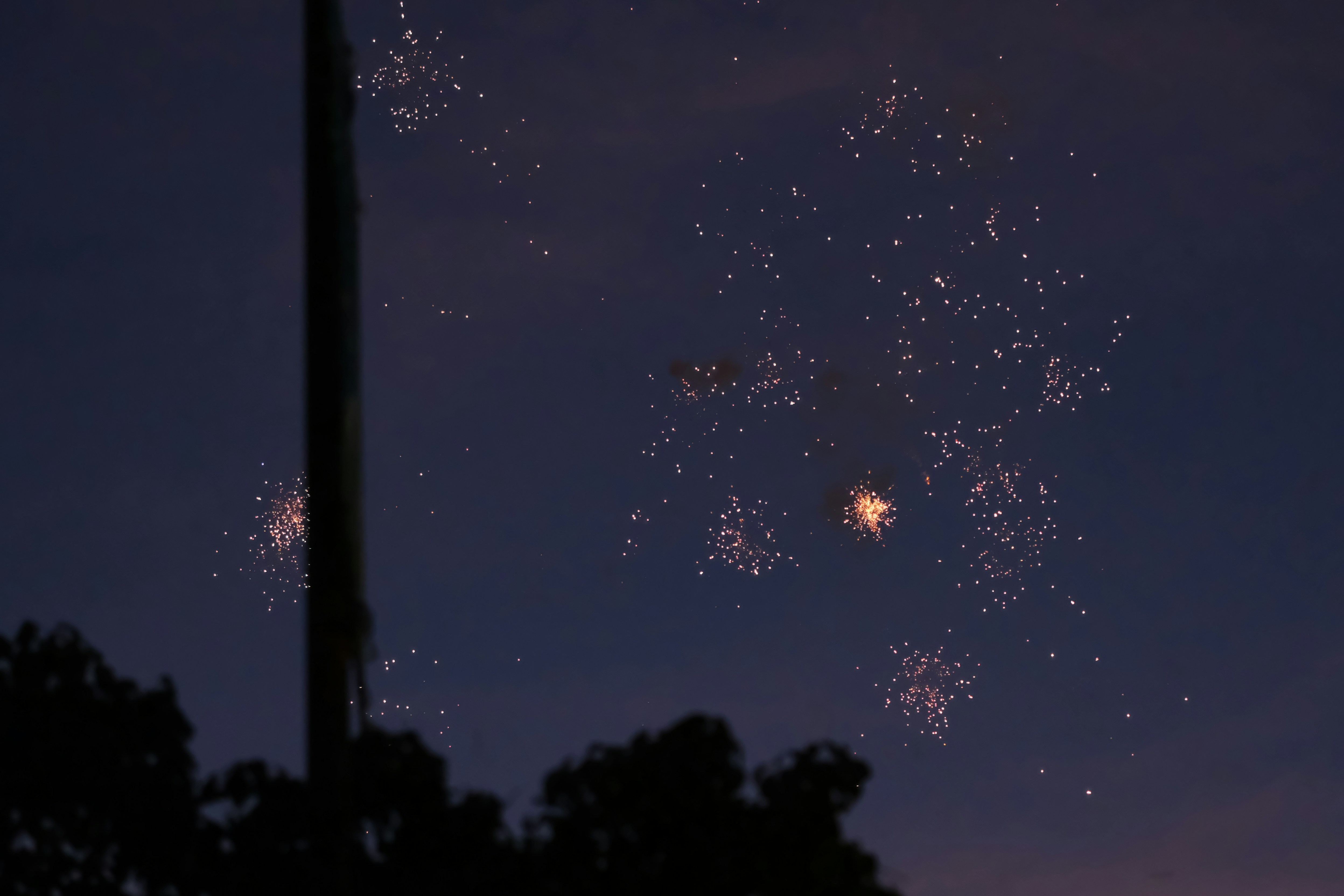 Night Sky Fire: A Quiet Burst Above Silhouetted Trees