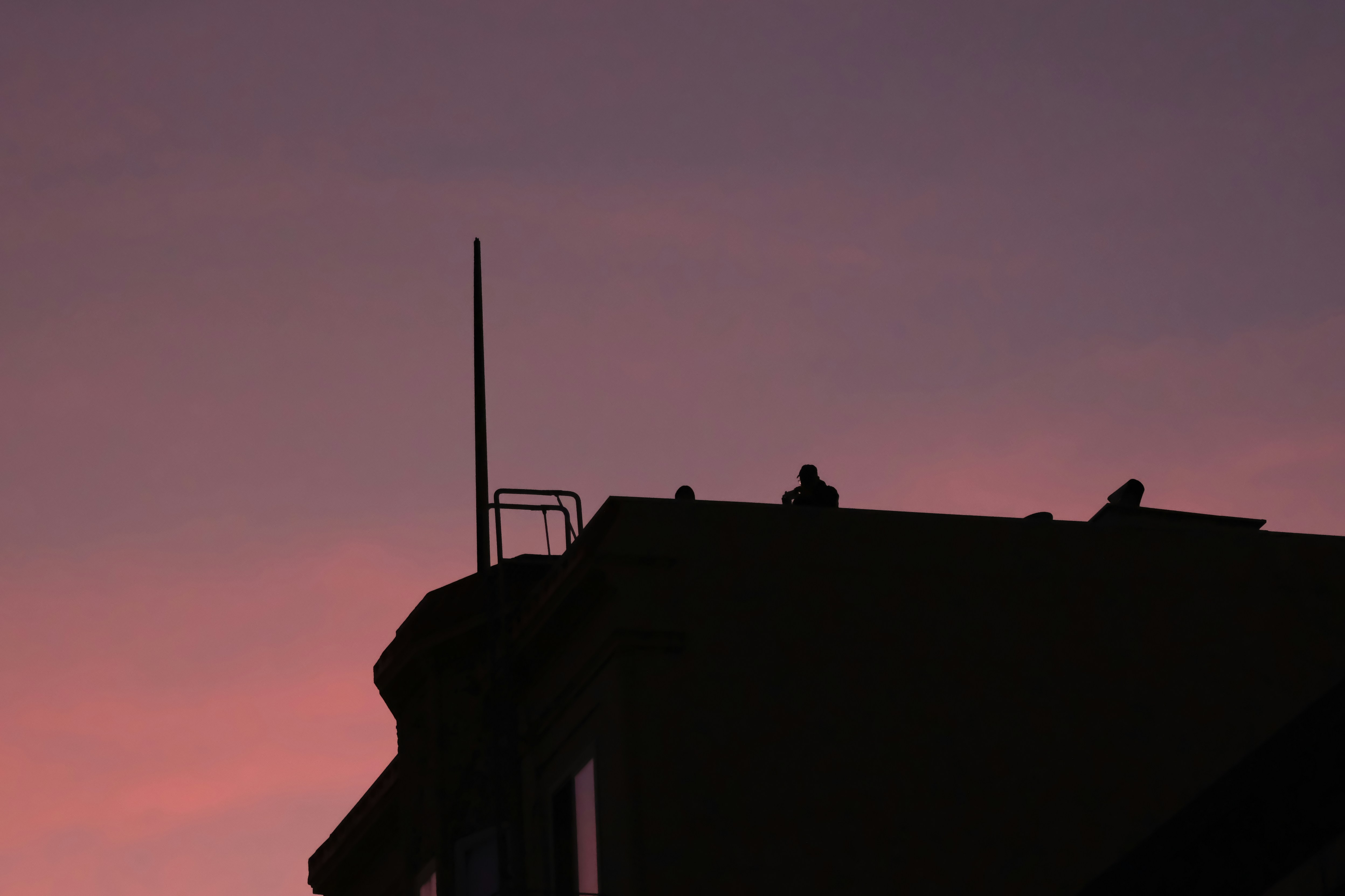 Silhouette at Dusk: Rooftop Watchers Against a Velvet Sky