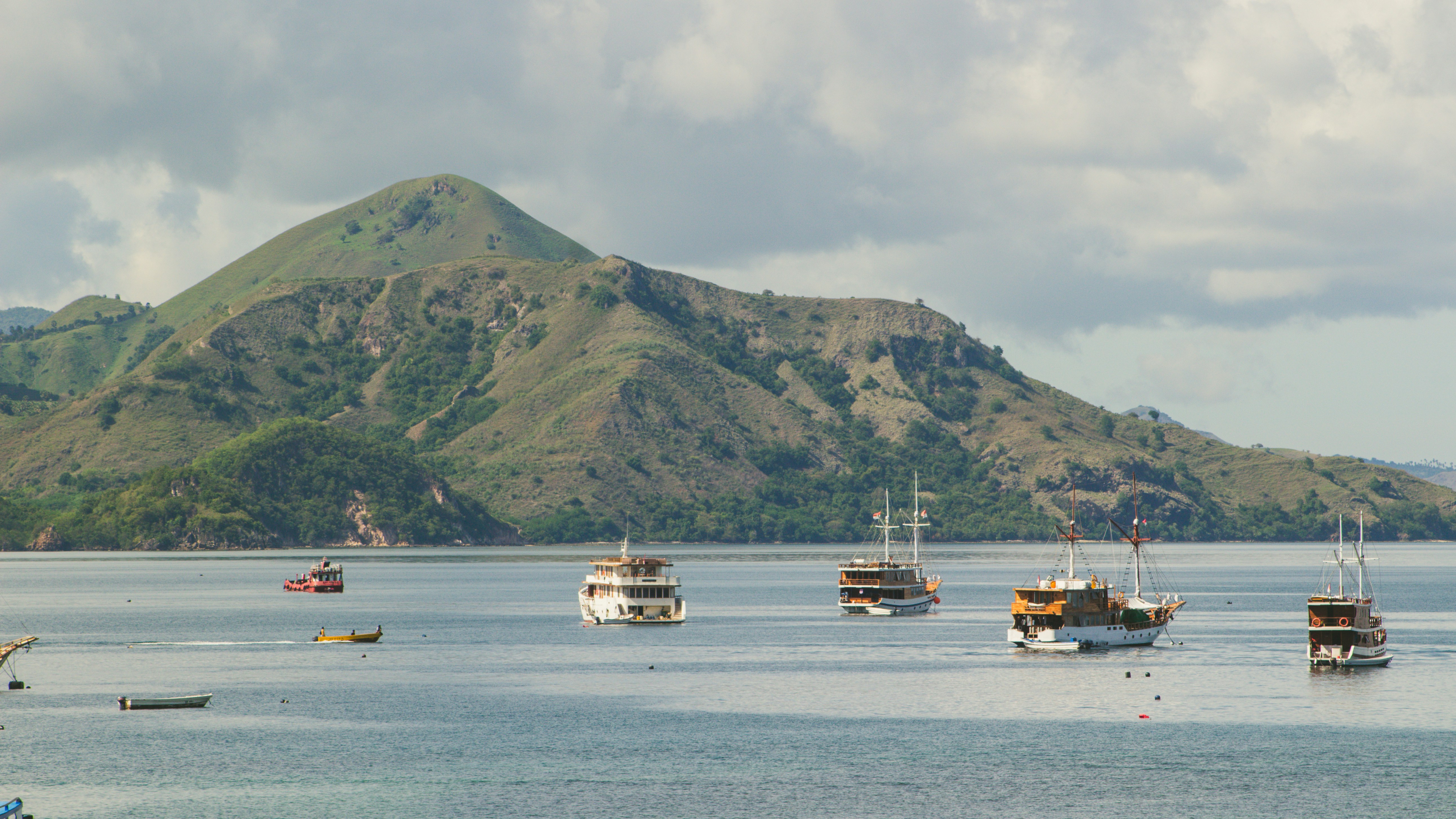 Harbor Silhouette: Boats at Rest Beneath a Rolling Hill
