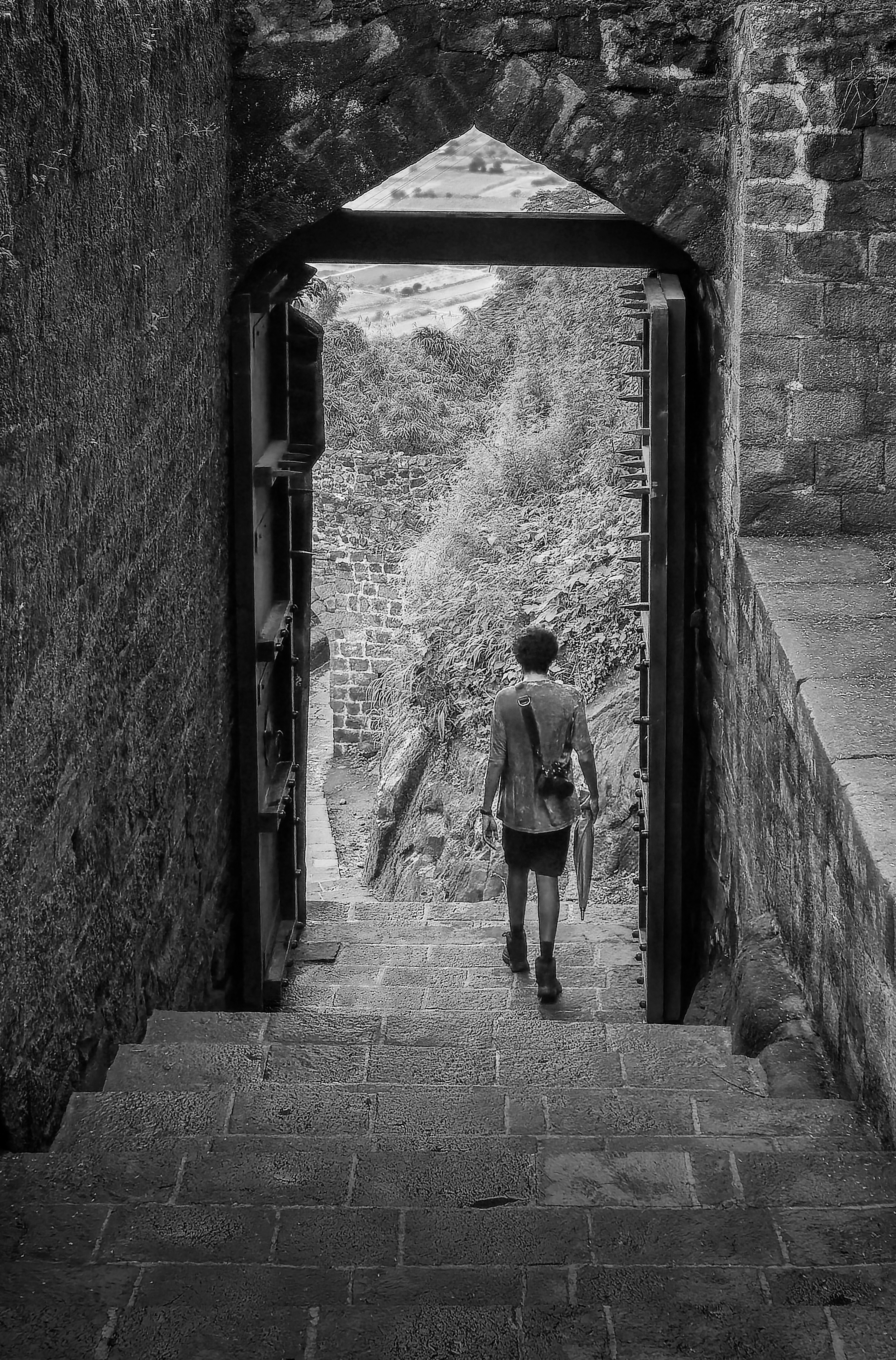 Through the Gate: A Silhouette Descends the Stone Staircase