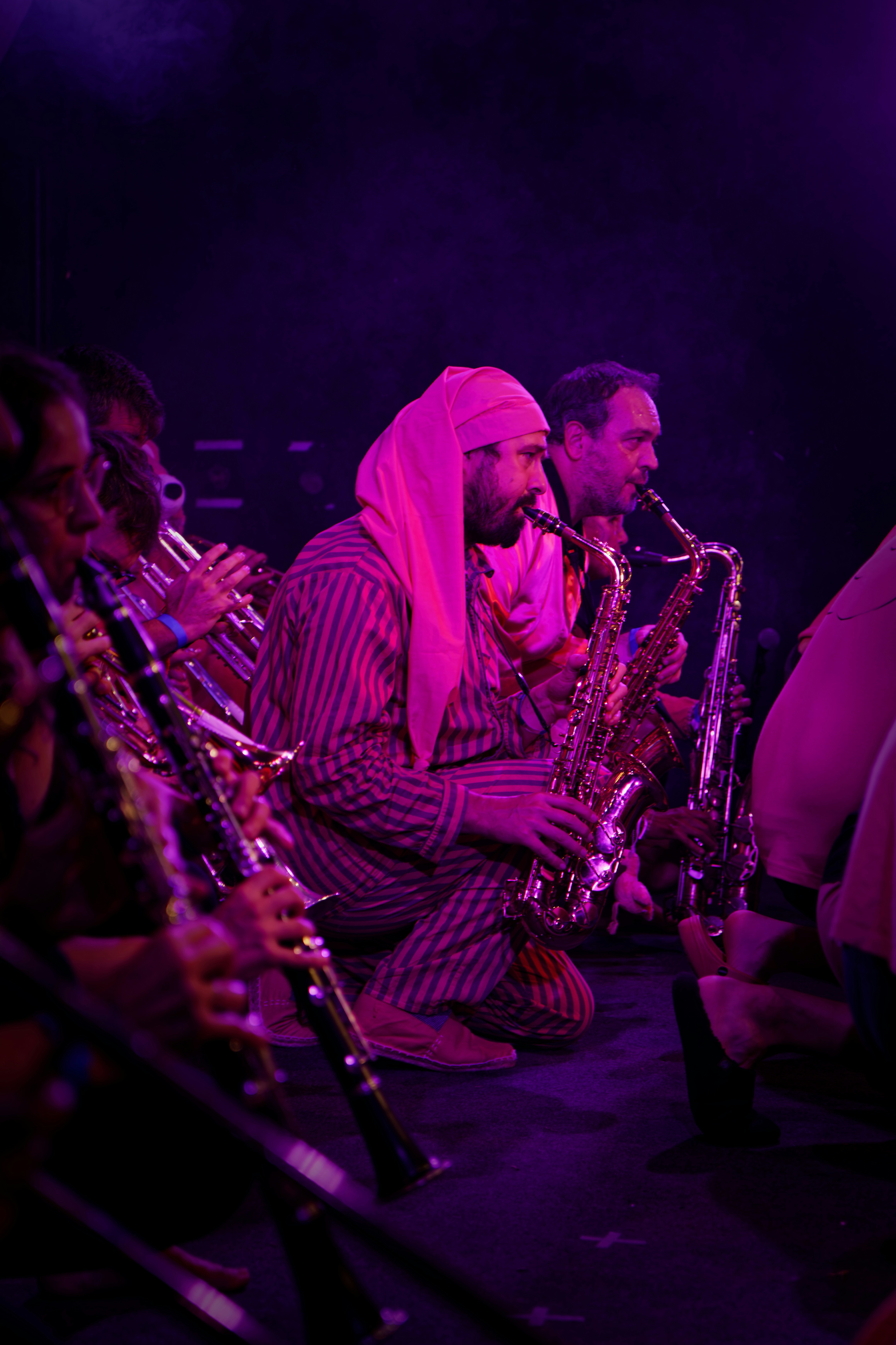 Midnight Brass: A kneeling saxophonist leads a echoed ensemble in violet haze