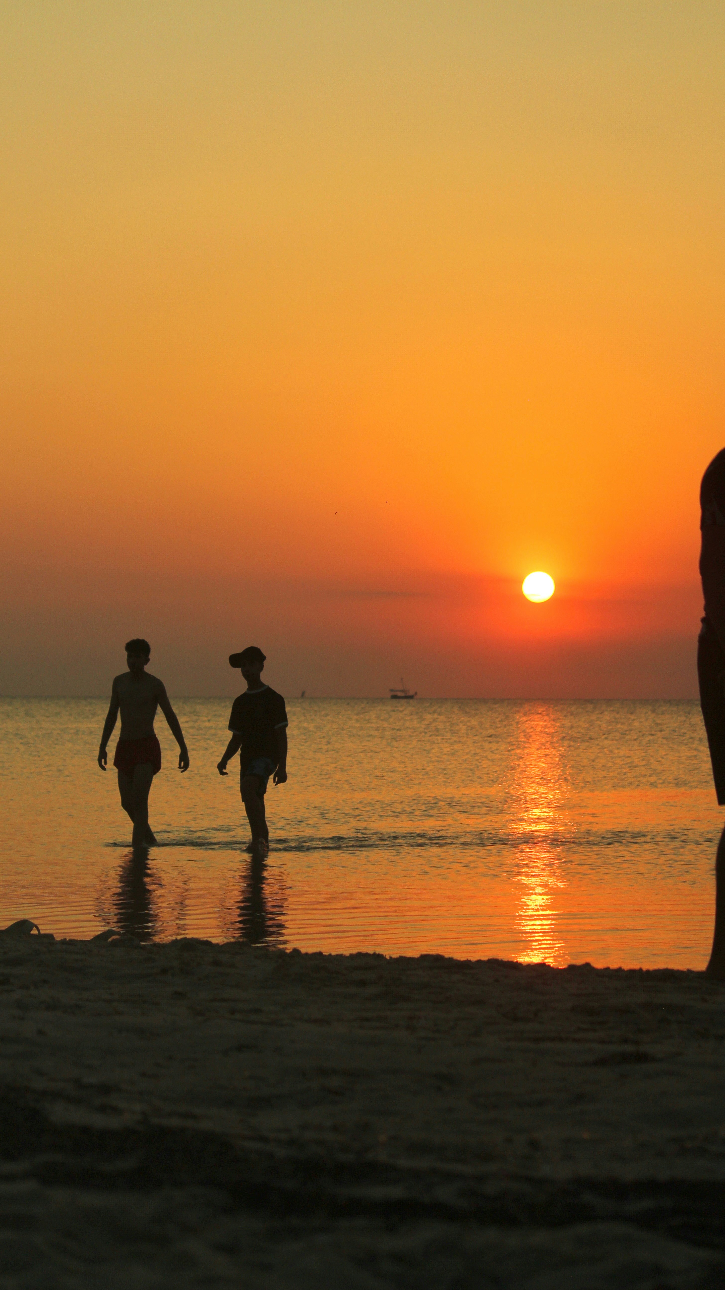 Silent silhouettes at sunset: friends wade through glowing tides
