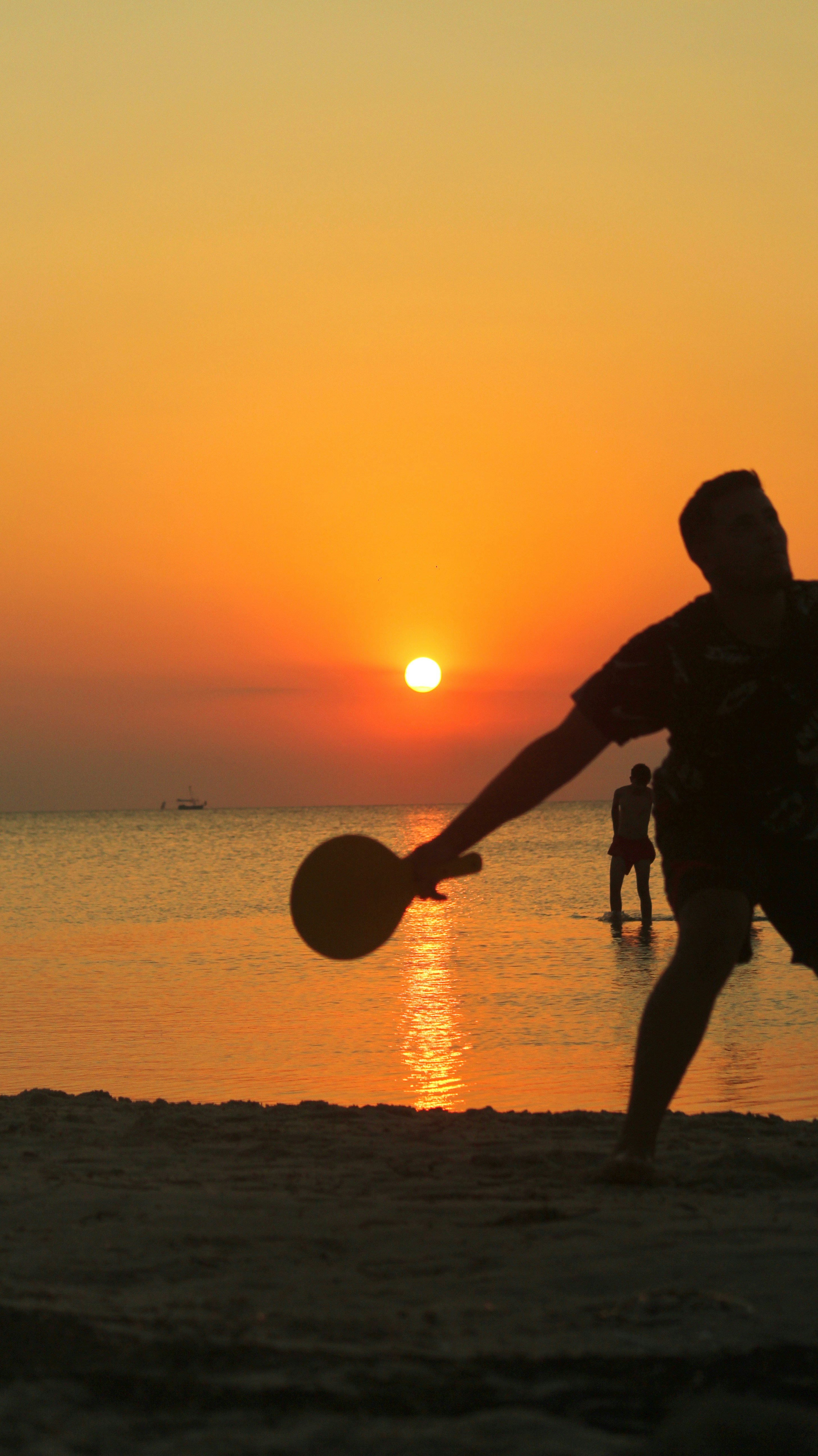 Sunset Beach Rally: silhouette of a player reaching toward the ball at dusk