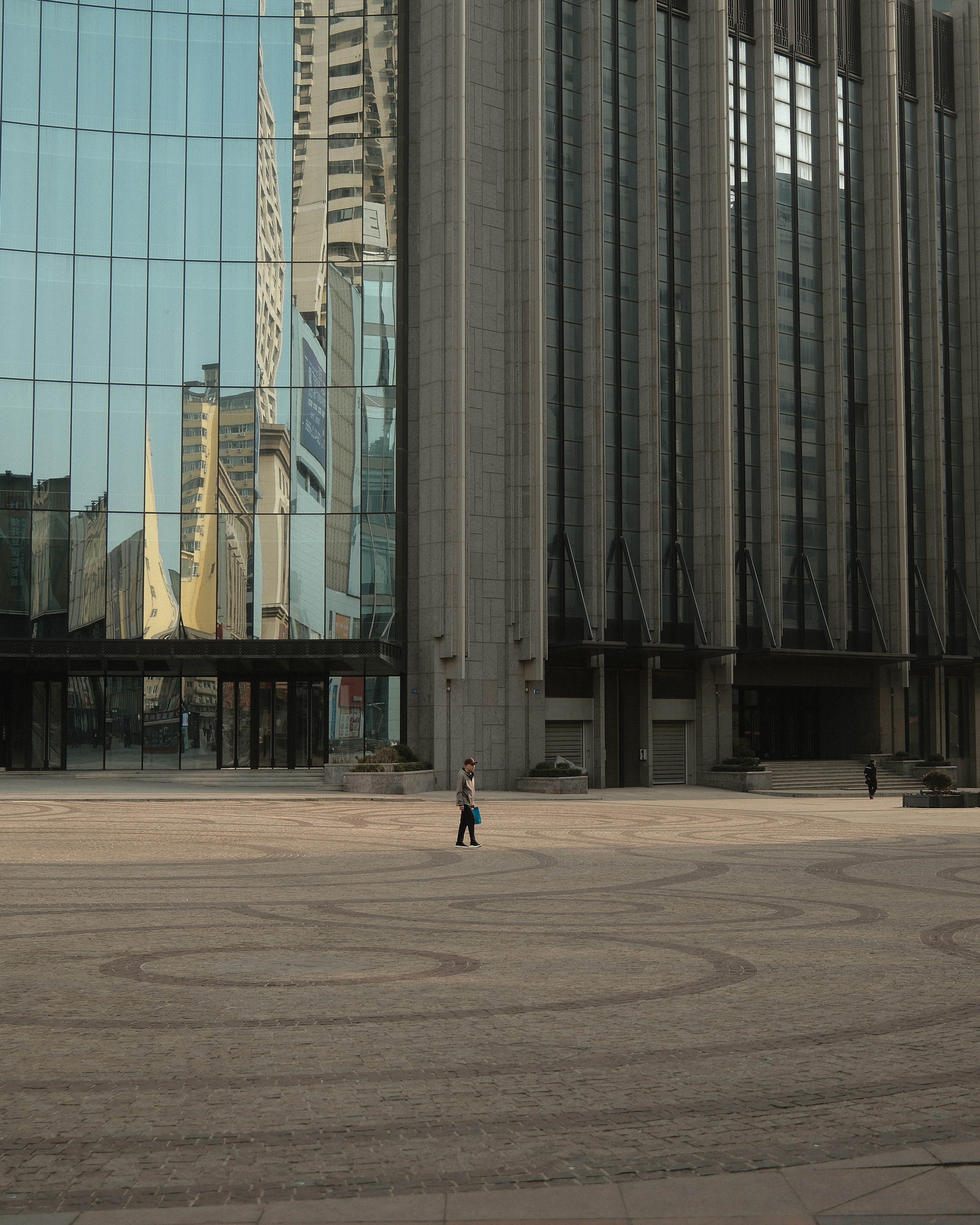  solitary figure in a glass-and-concrete plaza