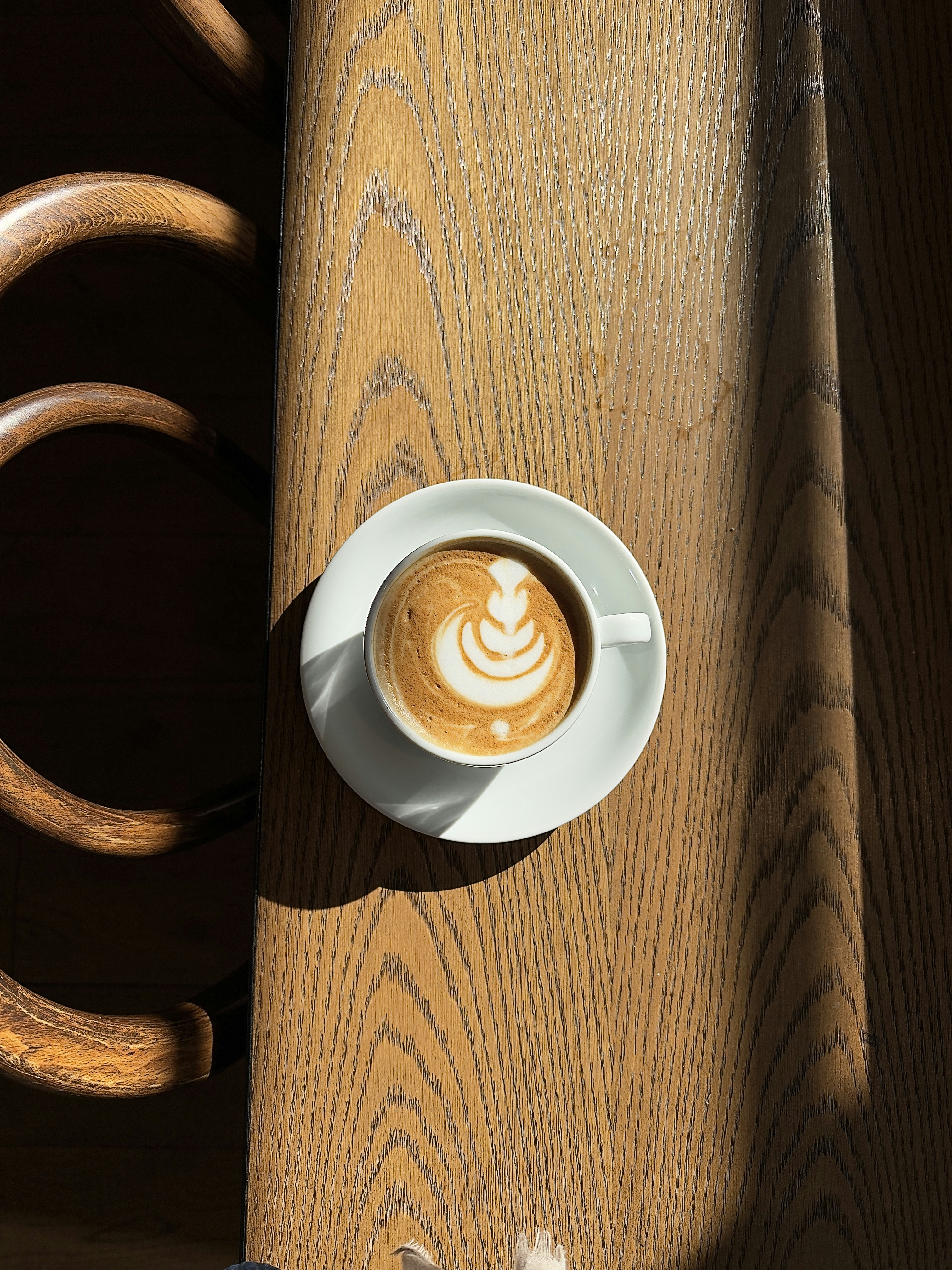 A Quiet Espresso Moment: Latte Art Centered on a Sunlit Wooden Table