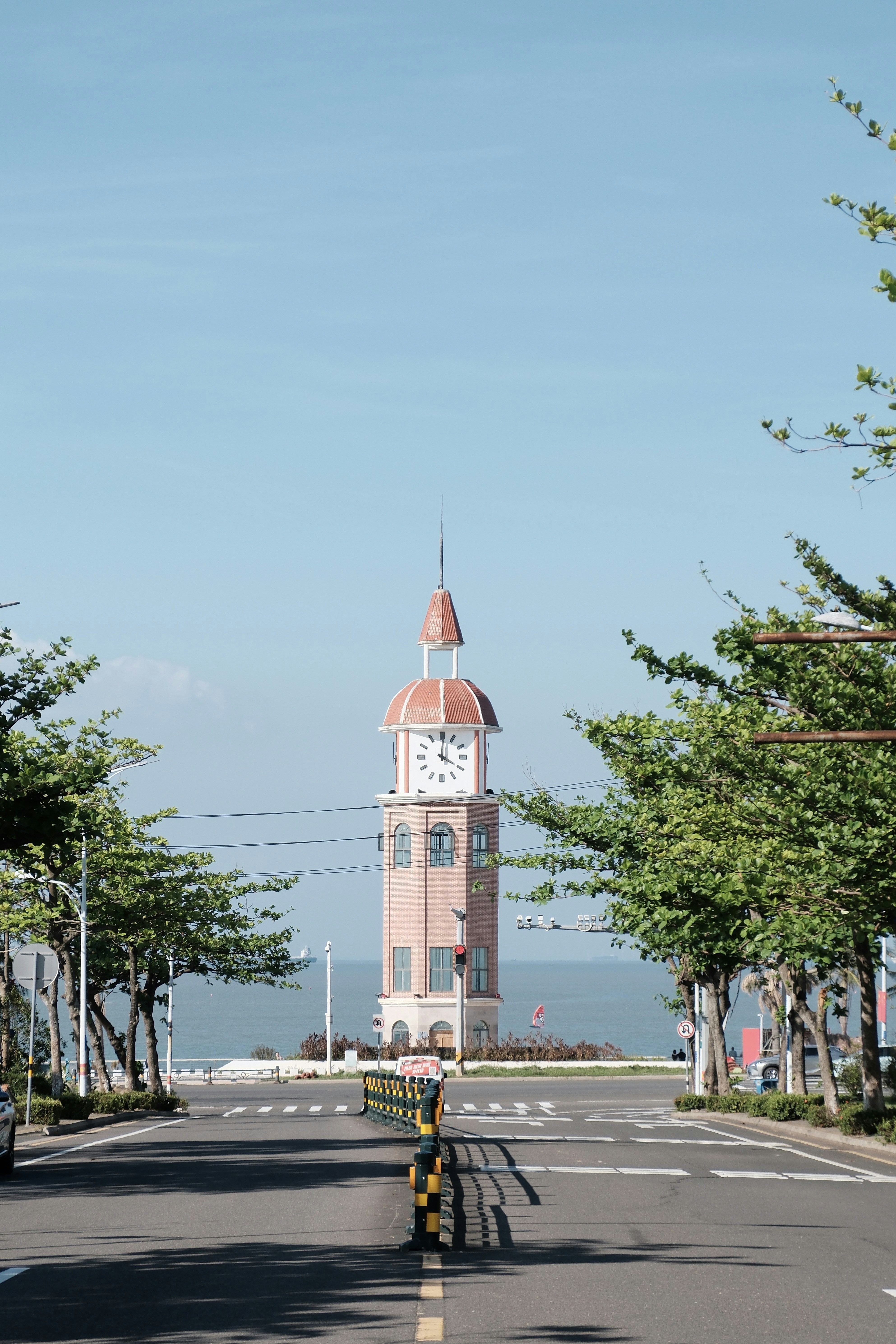 Clock Tower by the Sea: A Quiet Coastal Street Framed by Greenery