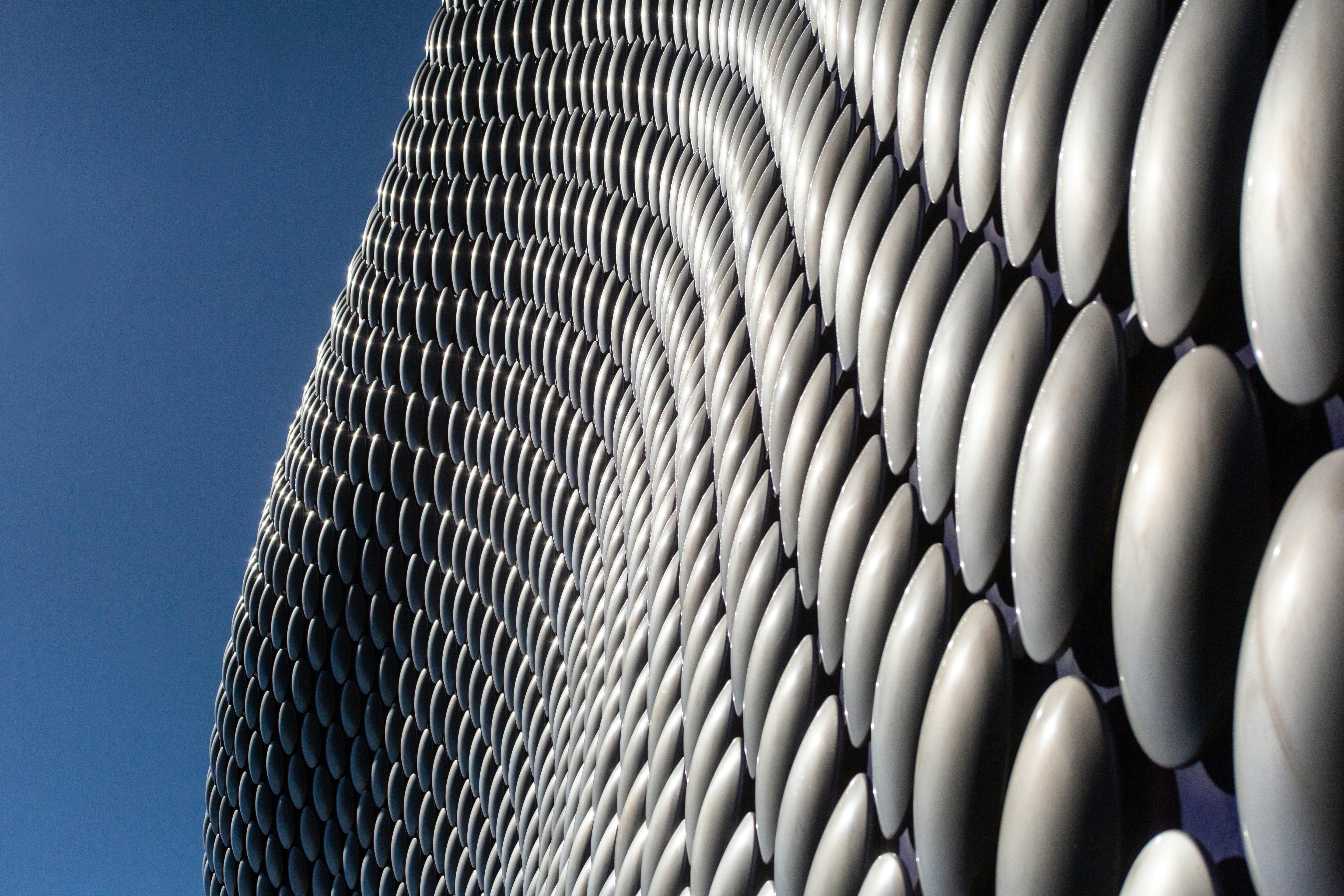 Ridge of reflective orbs: a curved metal facade under a clear blue sky