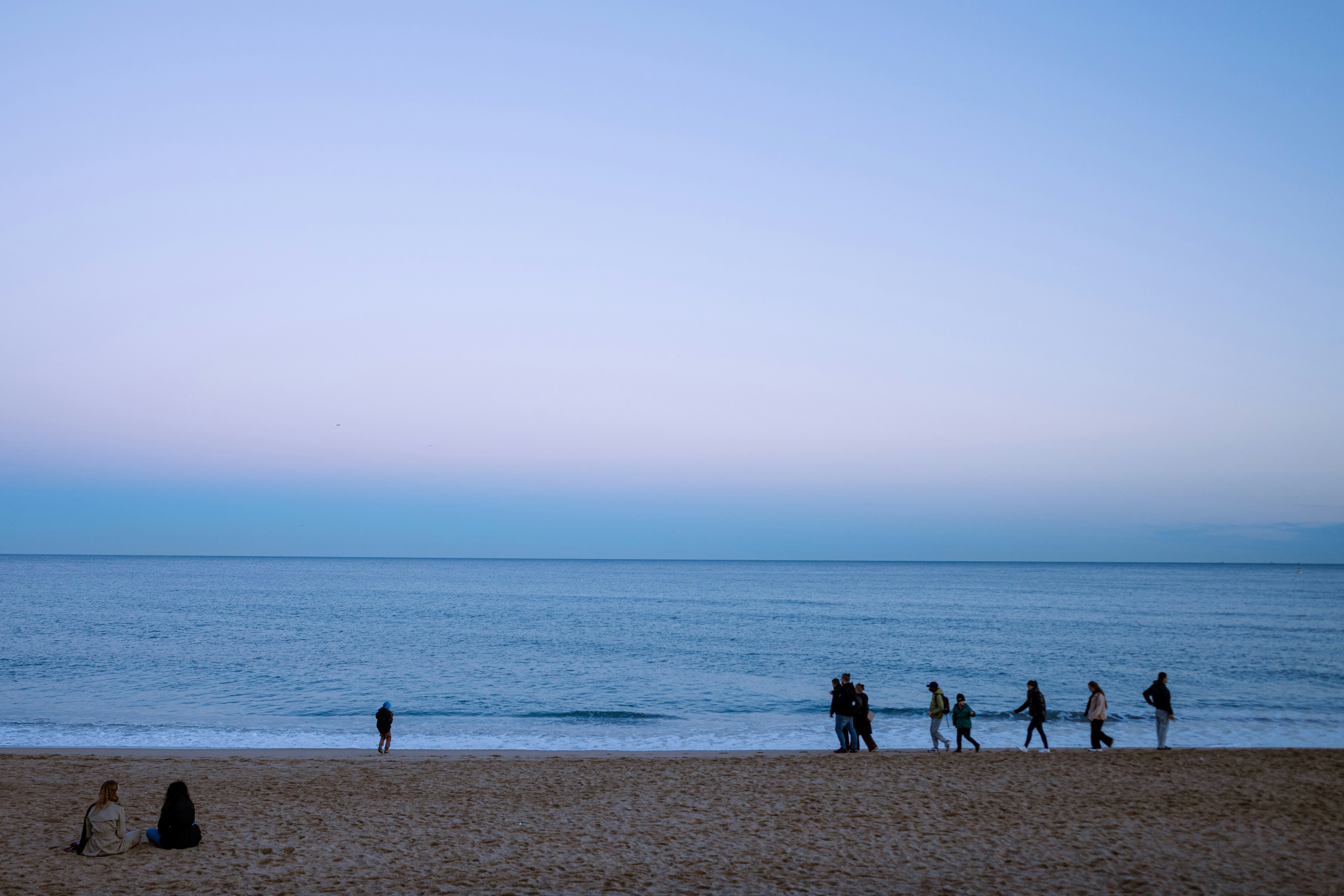 Distant Tide: silhouettes of beachgoers at blue hour