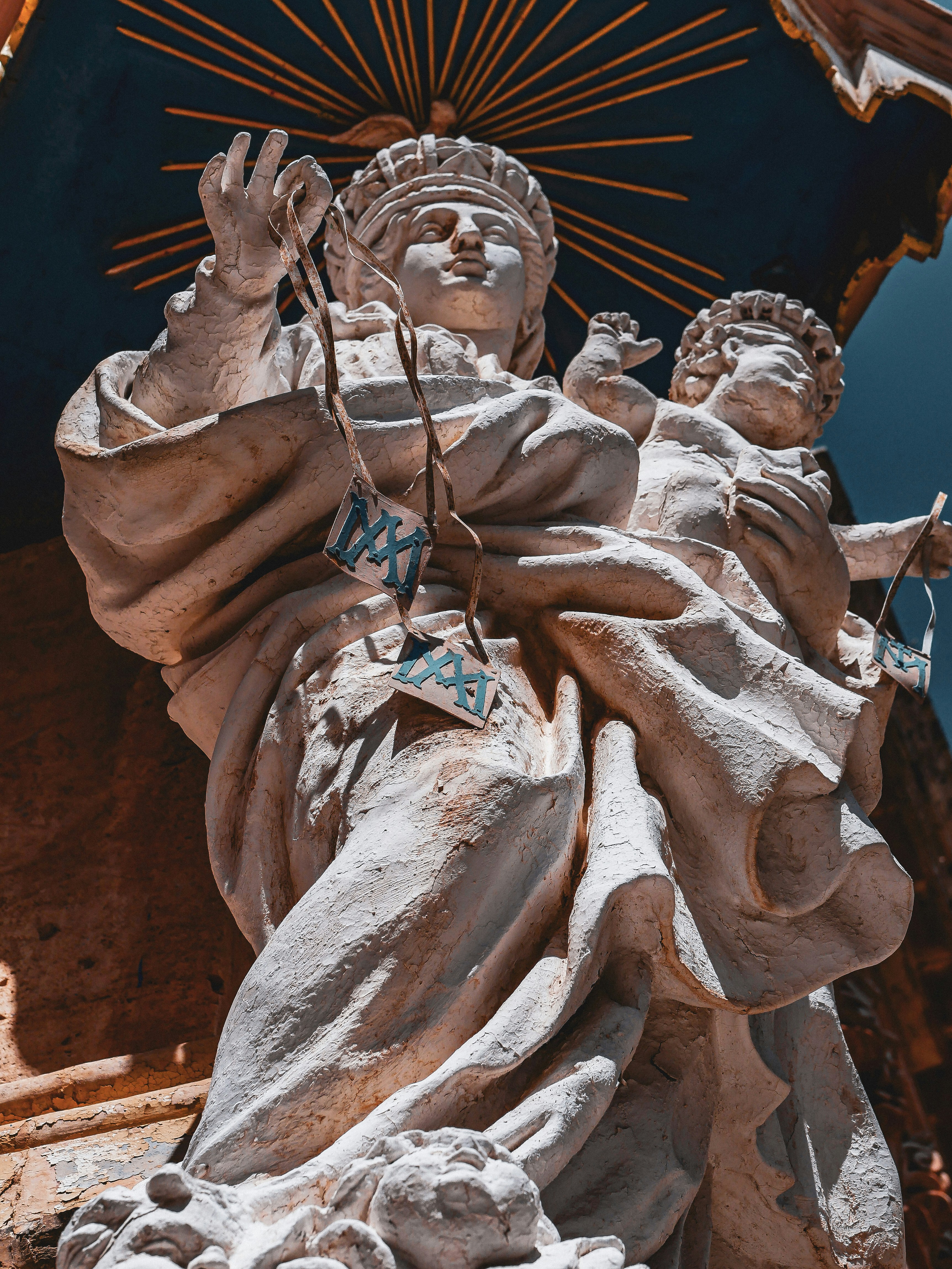Angelic Carved Relief: Statues With Strings of Prayer Tags in Sunlit Niche