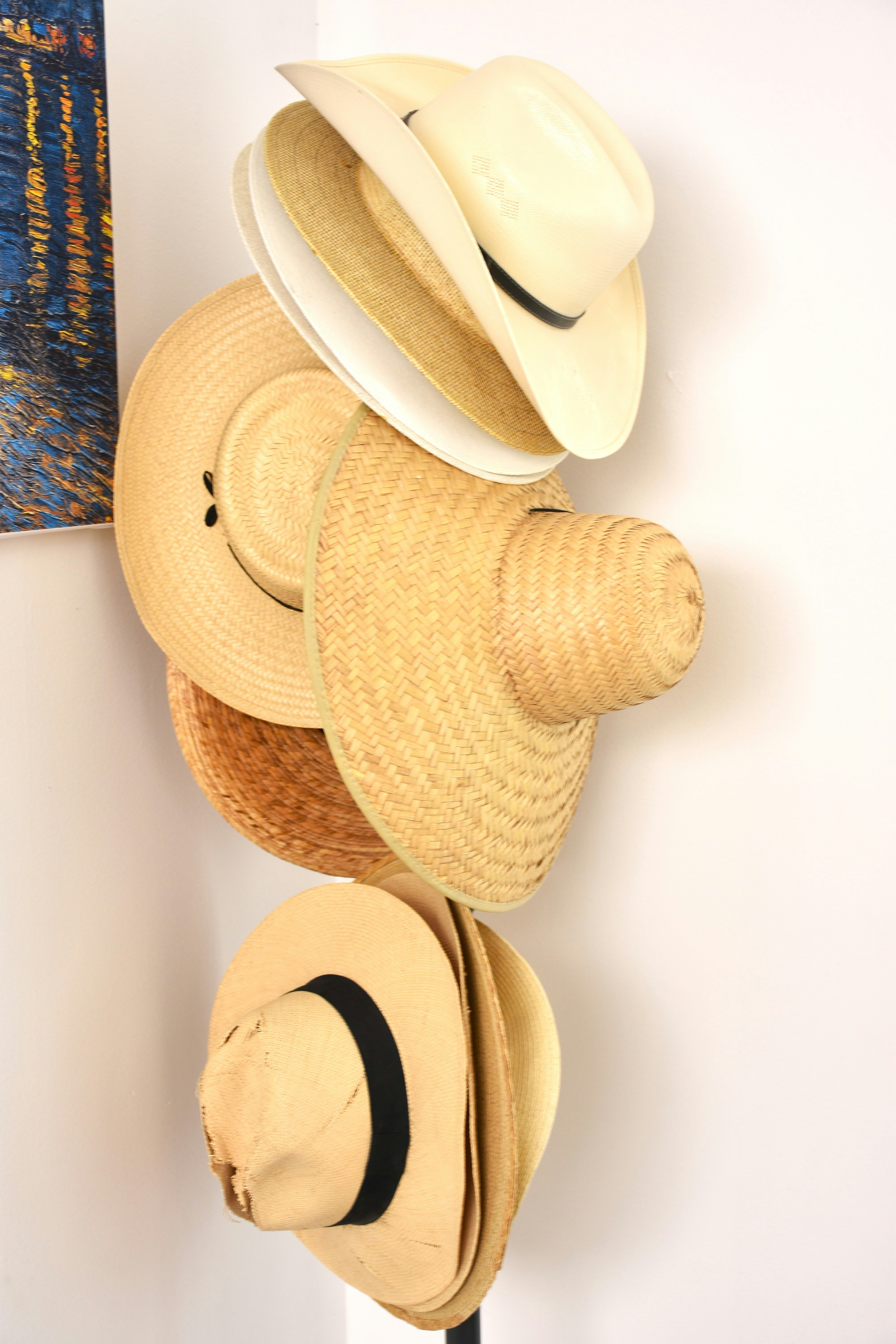 Stacked straw hats on a pale wall