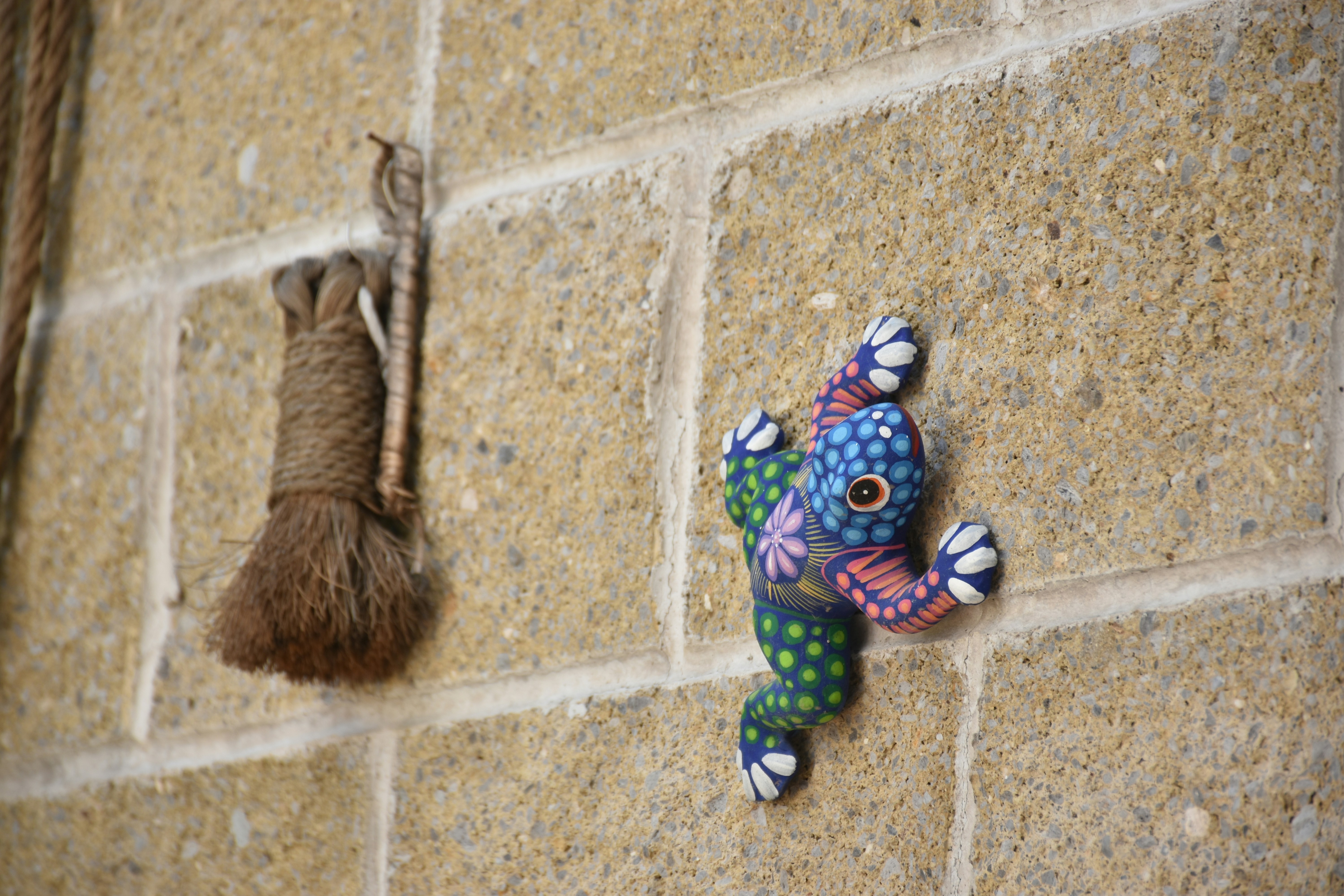 Colorful Gecko-Toy Clings to a Textured Brick Wall
