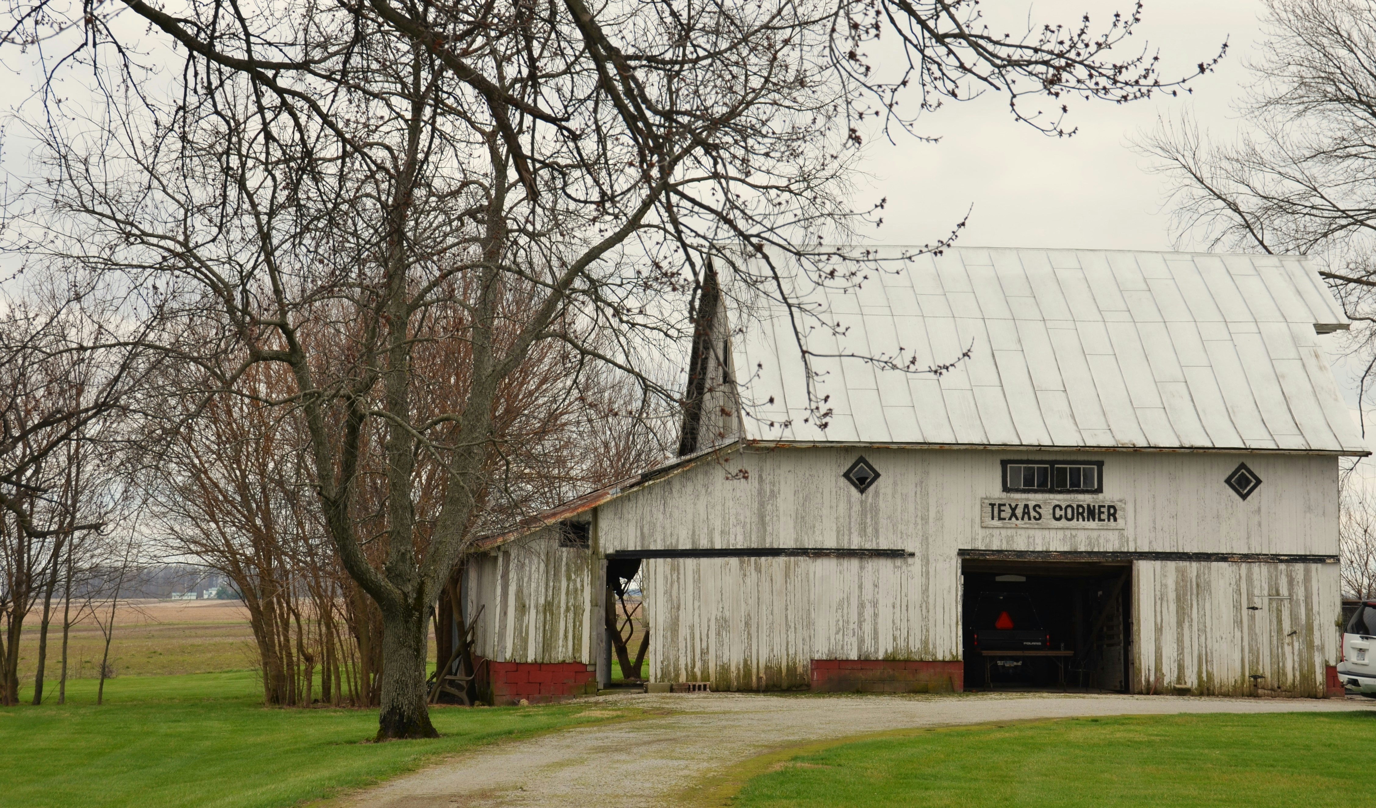 Weathered Texas Corner: A Gypsy Barn with Pale Roof and Open Gates