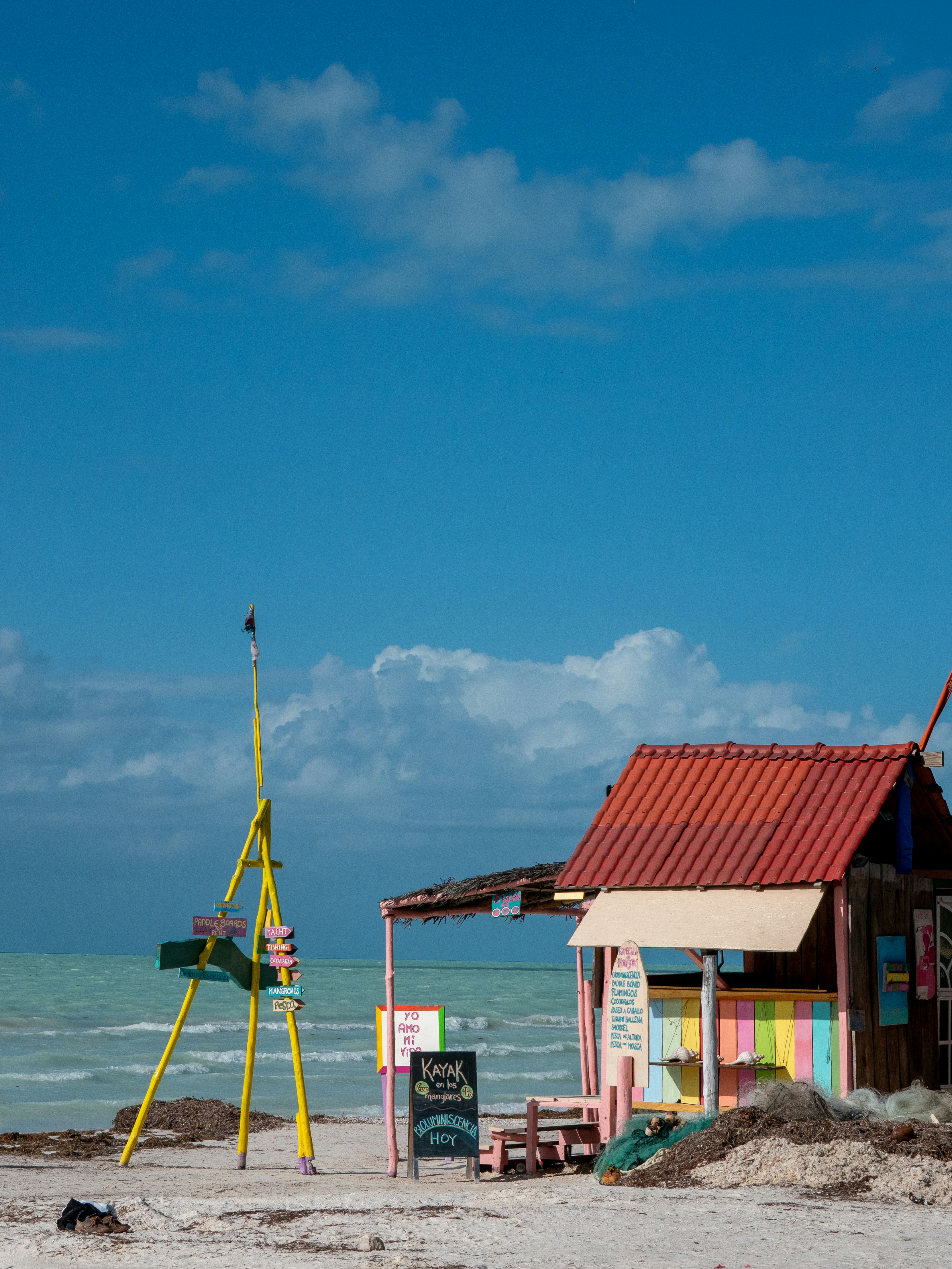 Sunlit Beach Shack and Colorful Signposts by the Turquoise Sea