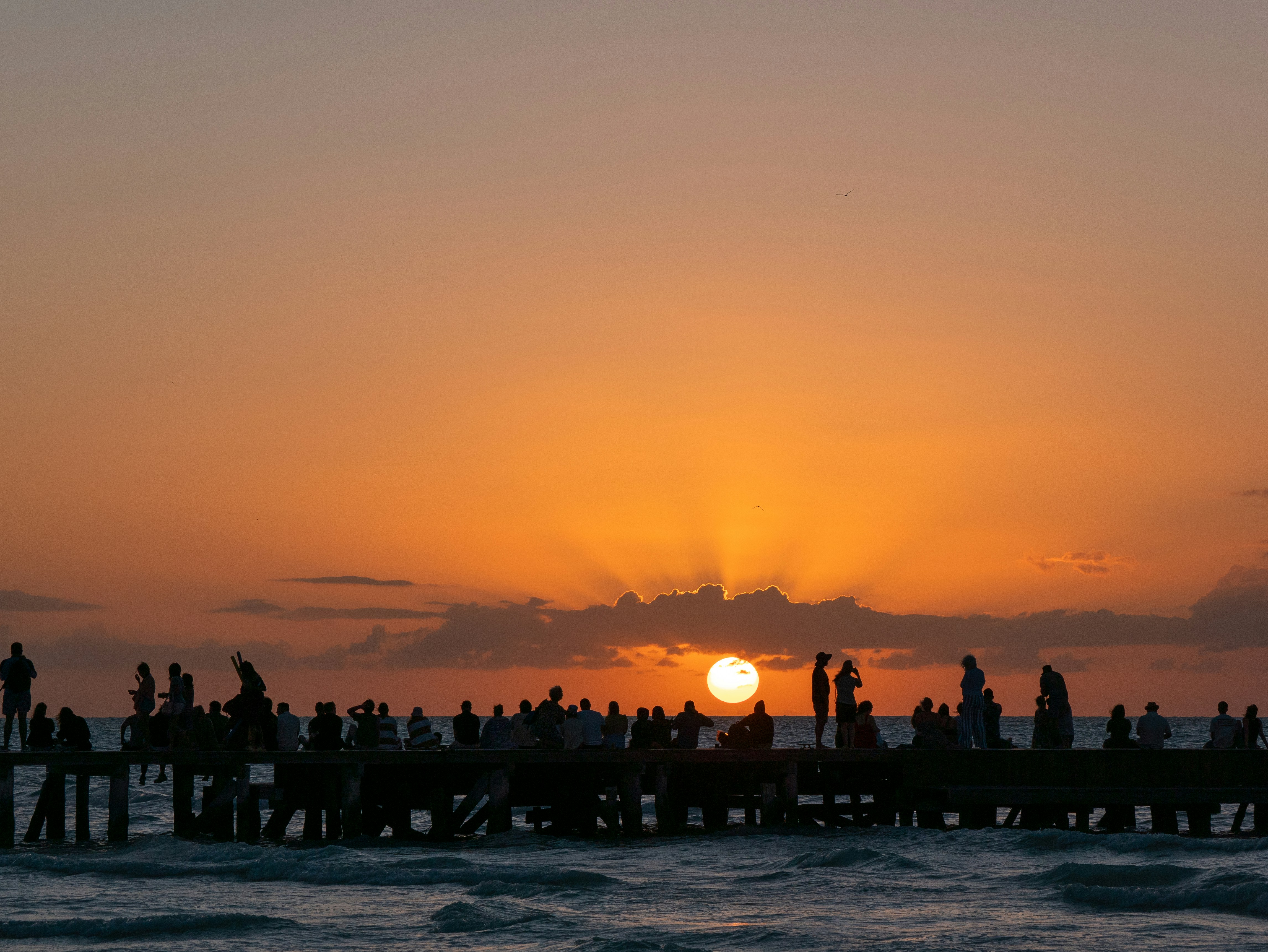 Sunset Silhouette: A Pierful Crowd Beneath an Ember Horizon