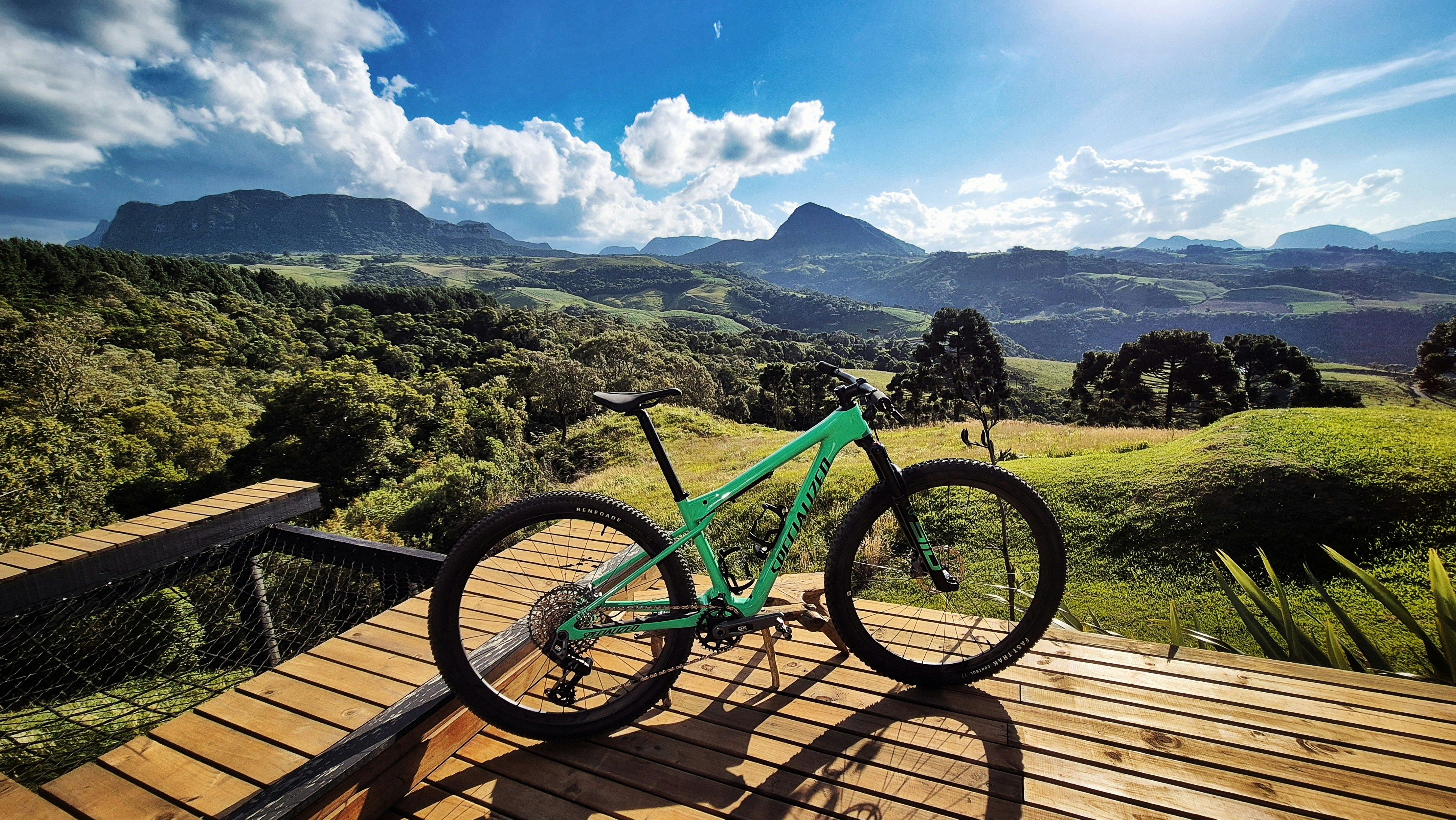 Green MTB on a sunlit ridge over rolling hills