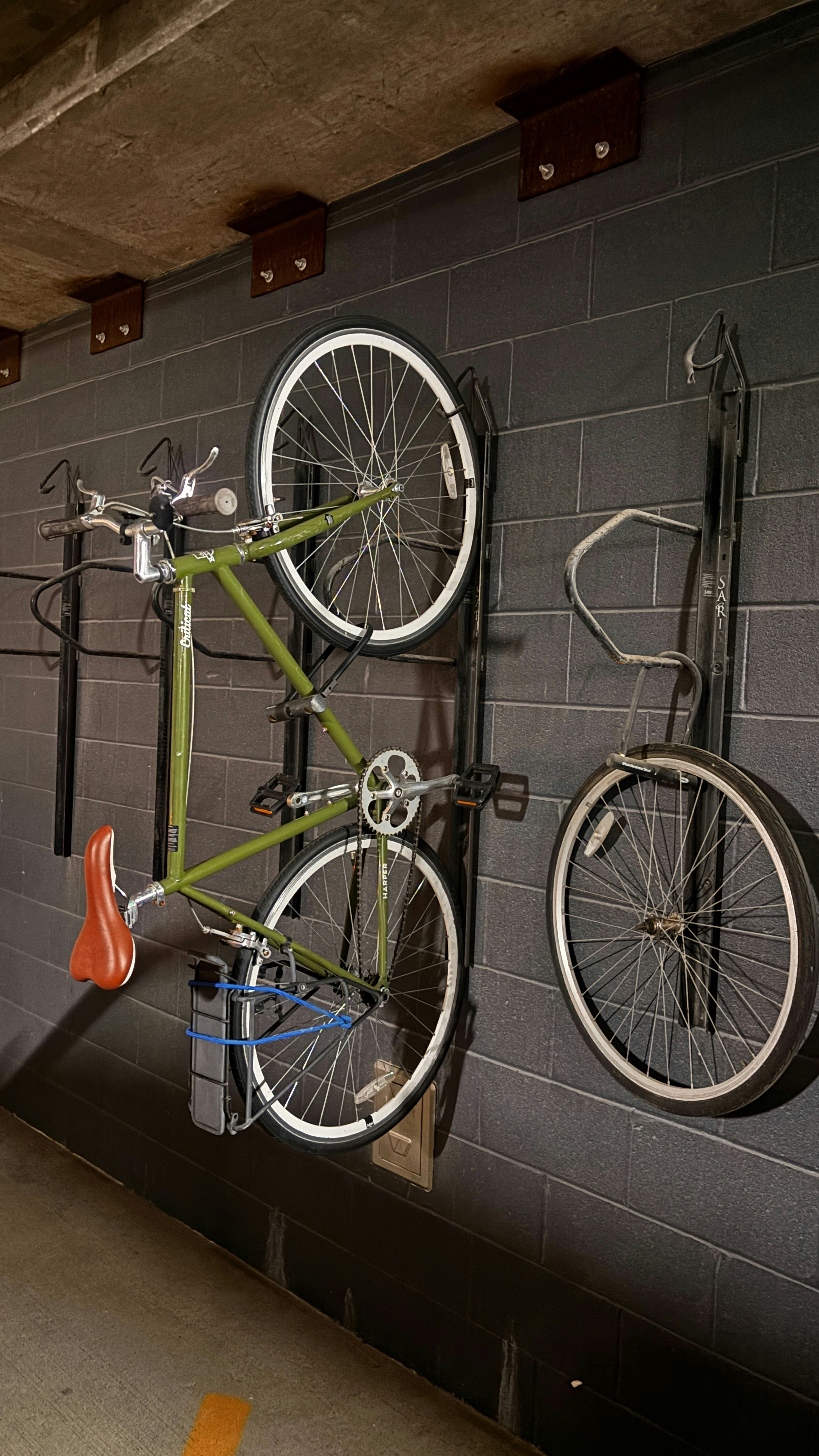 Green bicycle hanging on a dark cinder block wall
