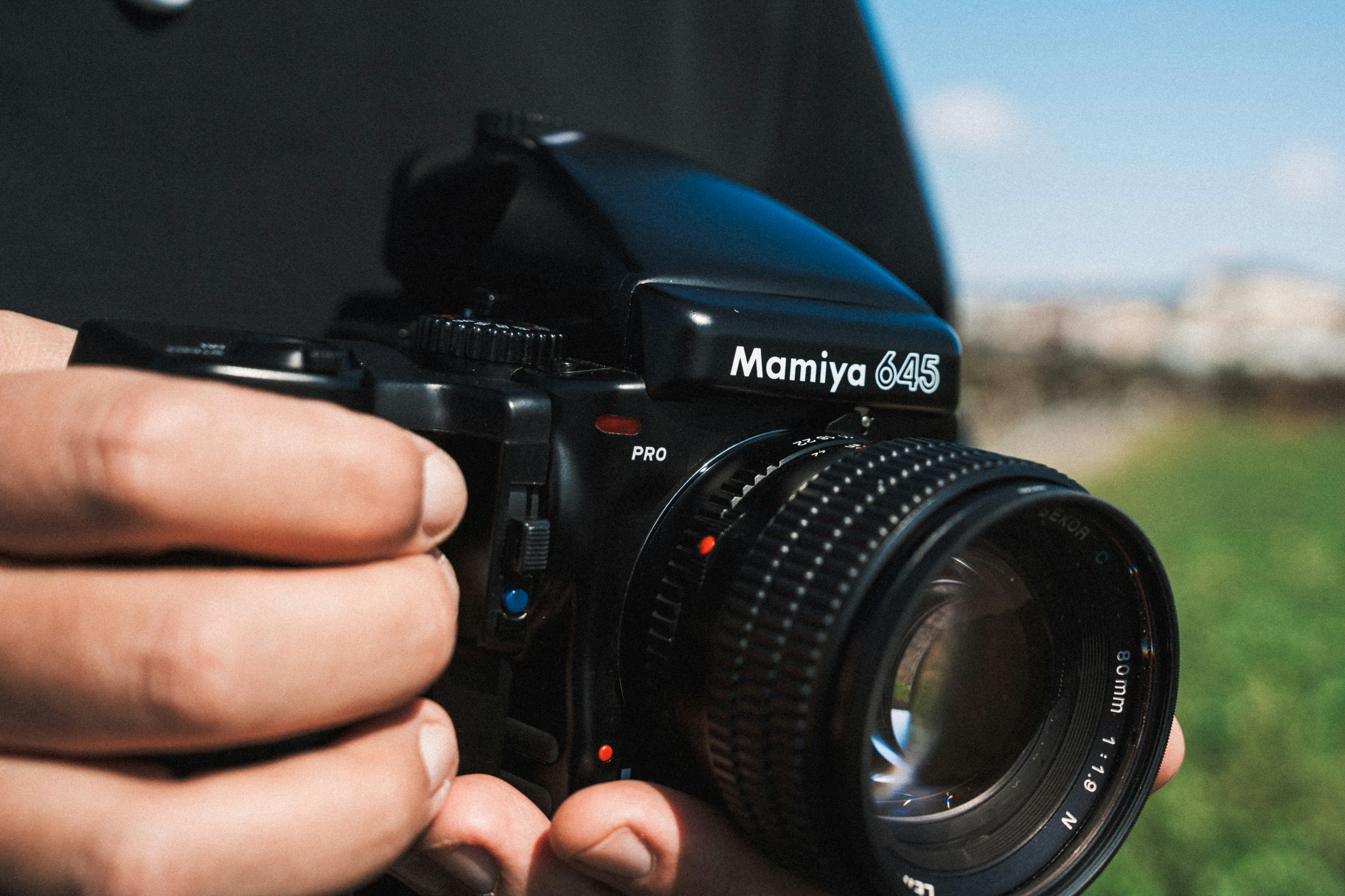 Close-up on a handheld Mamiya 645: A tactile moment with a vintage film-style camera